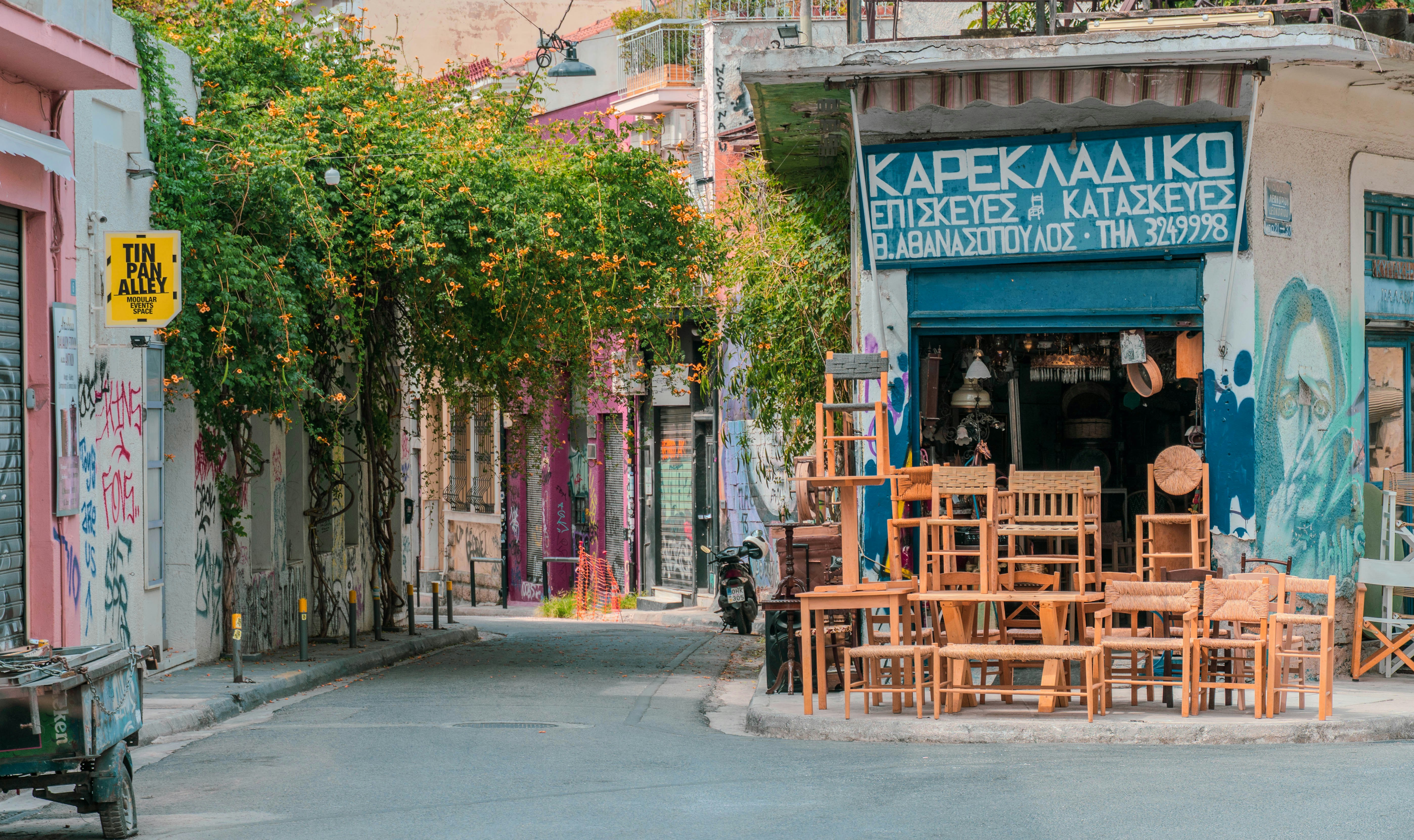 Sunlit Street Café: A Quiet Greek Lane with Stacked Chairs