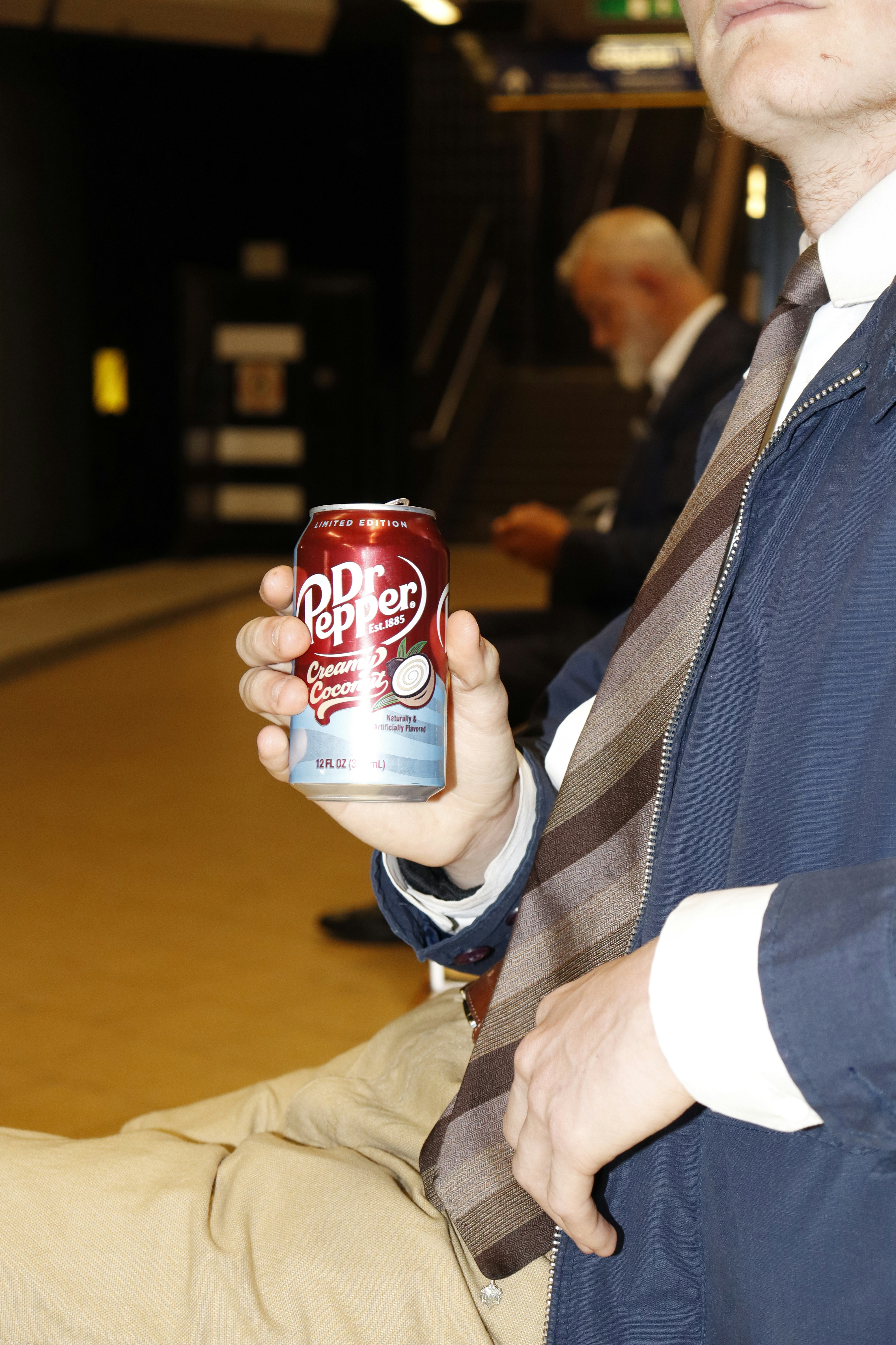 A person in a blue jacket holding a can of Dr Pepper Creamy Coconut soda