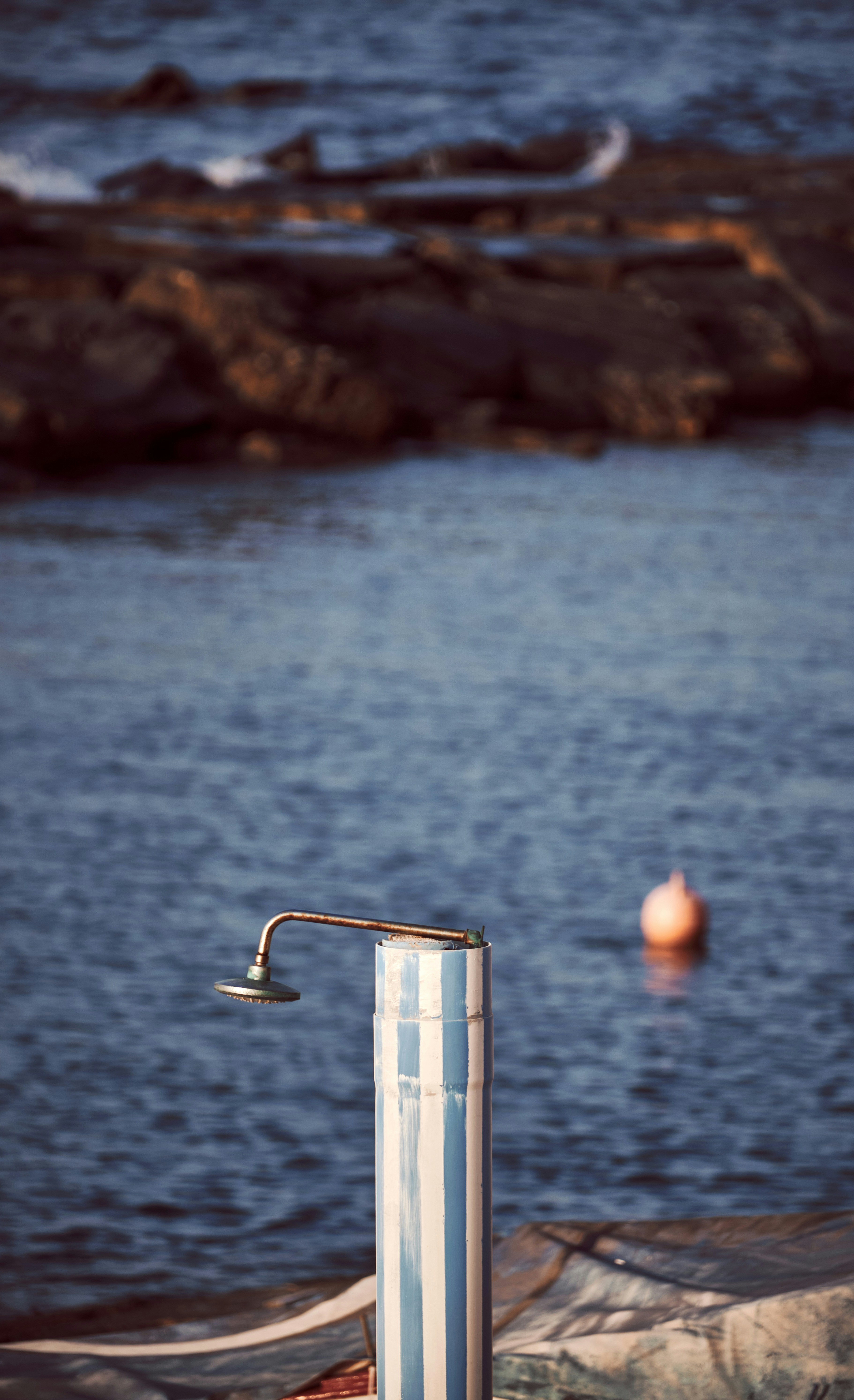 Blue-and-white striped shore shower under a quiet harbor at dusk
