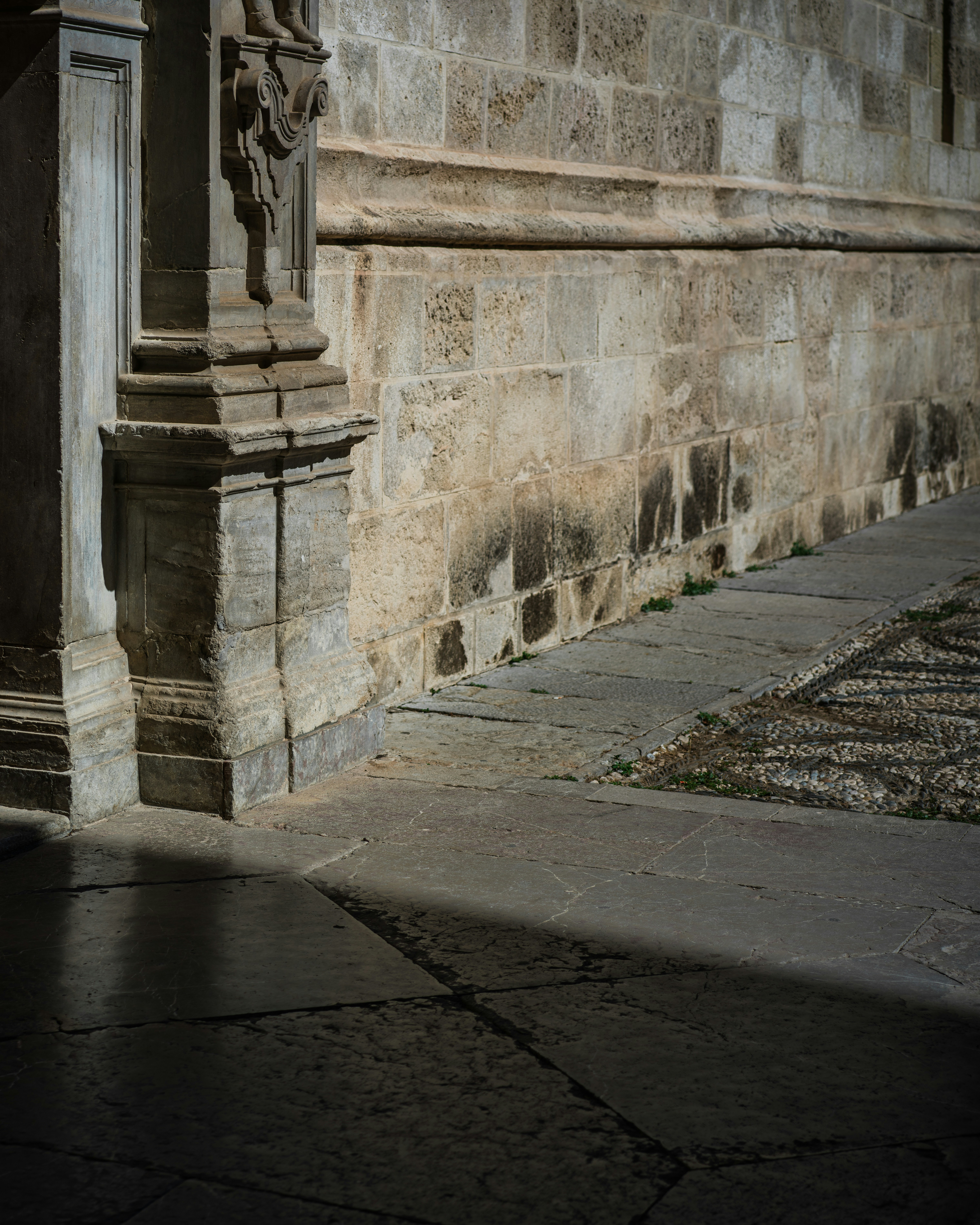 Shadowed Stone Corridor: Sunlit Facade and Quiet Ground
