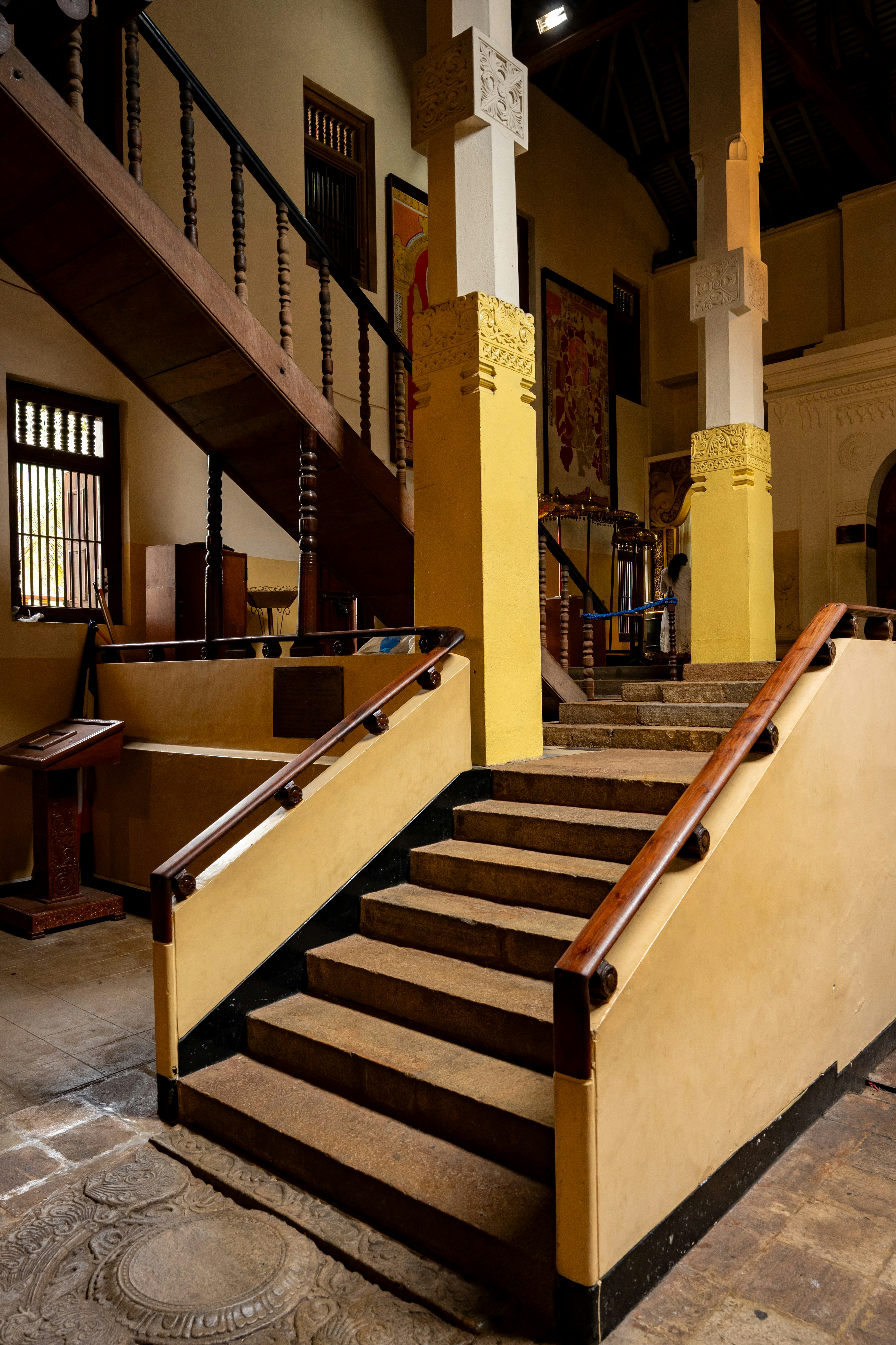 Sunlit stairs and yellow columns guide the descent through a historic interior