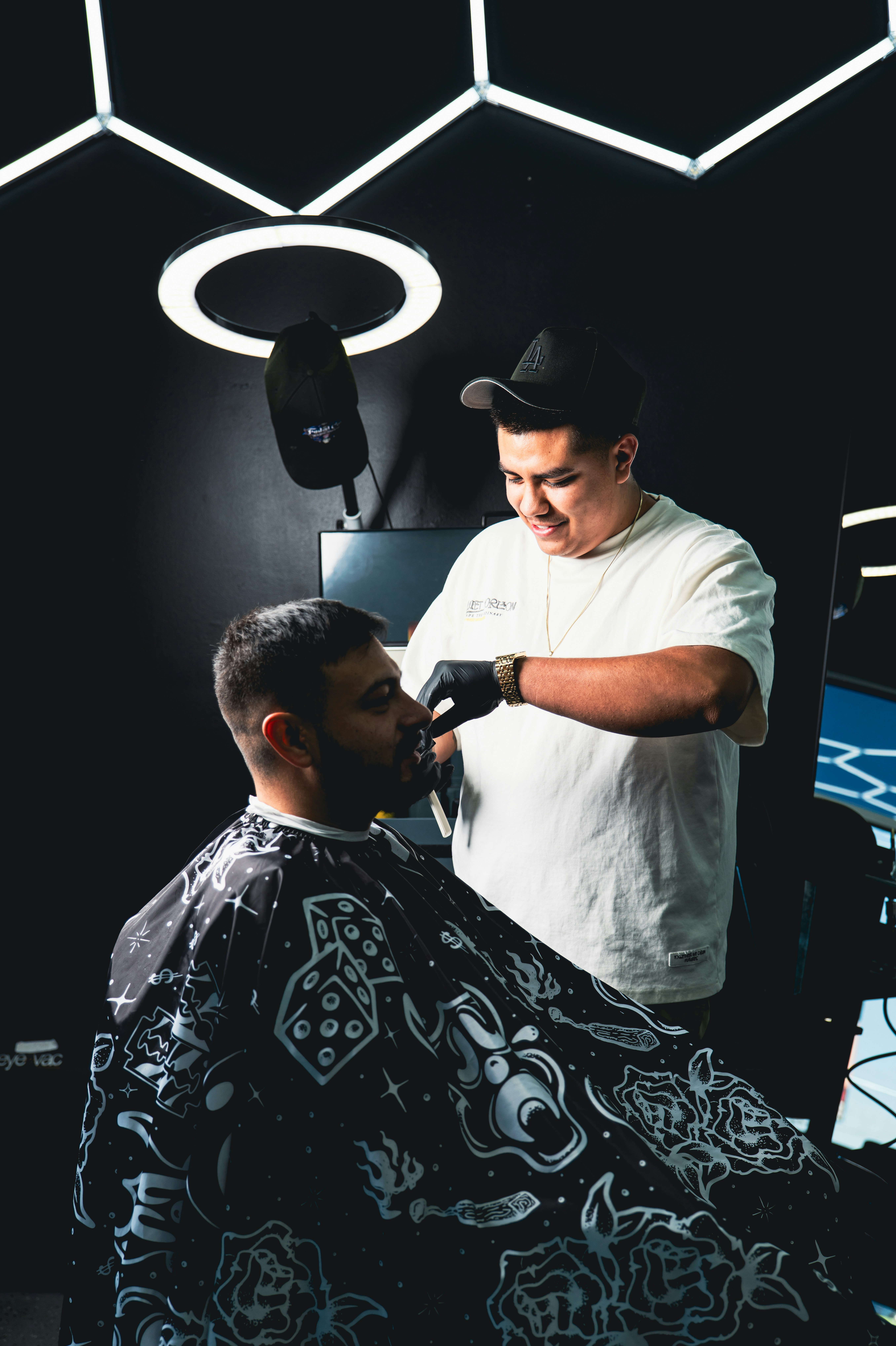 Focused Fade: A Barber in White Tees Sculpting Lines Under Neon Geometry