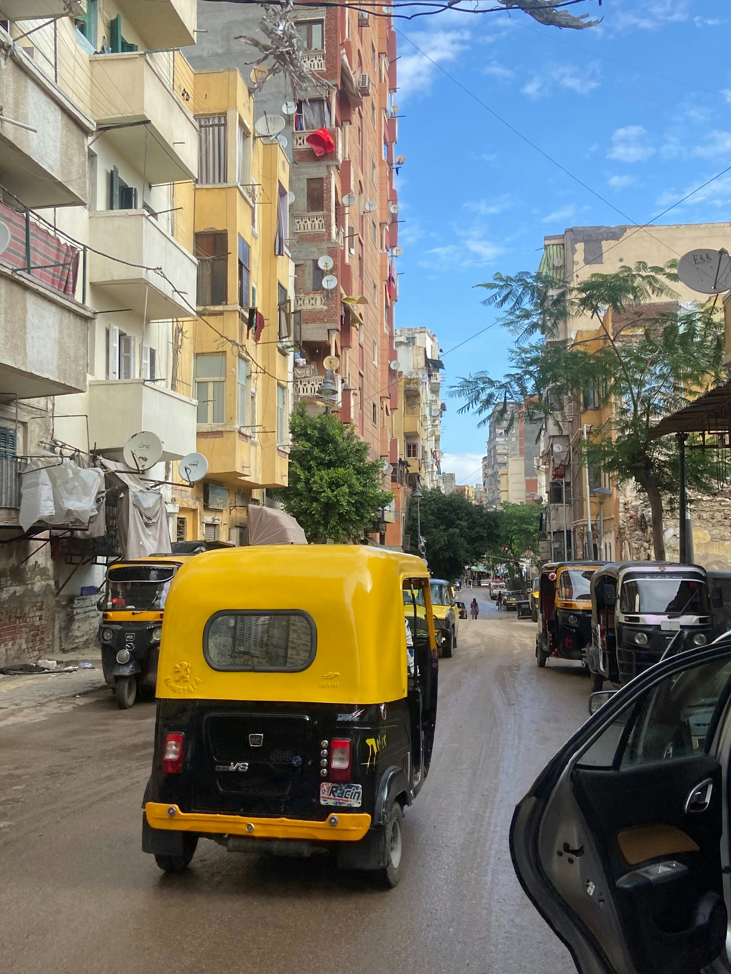 Yellow Tuk-Tuk Cadence: Street Scene Under a Blue City Sky