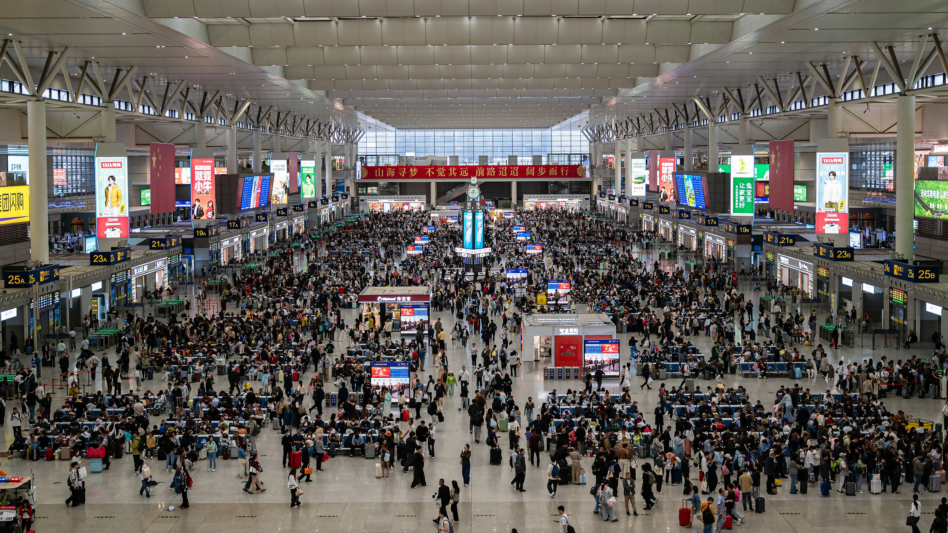 Massive concourse, sea of travelers converging toward a distant terminal hub