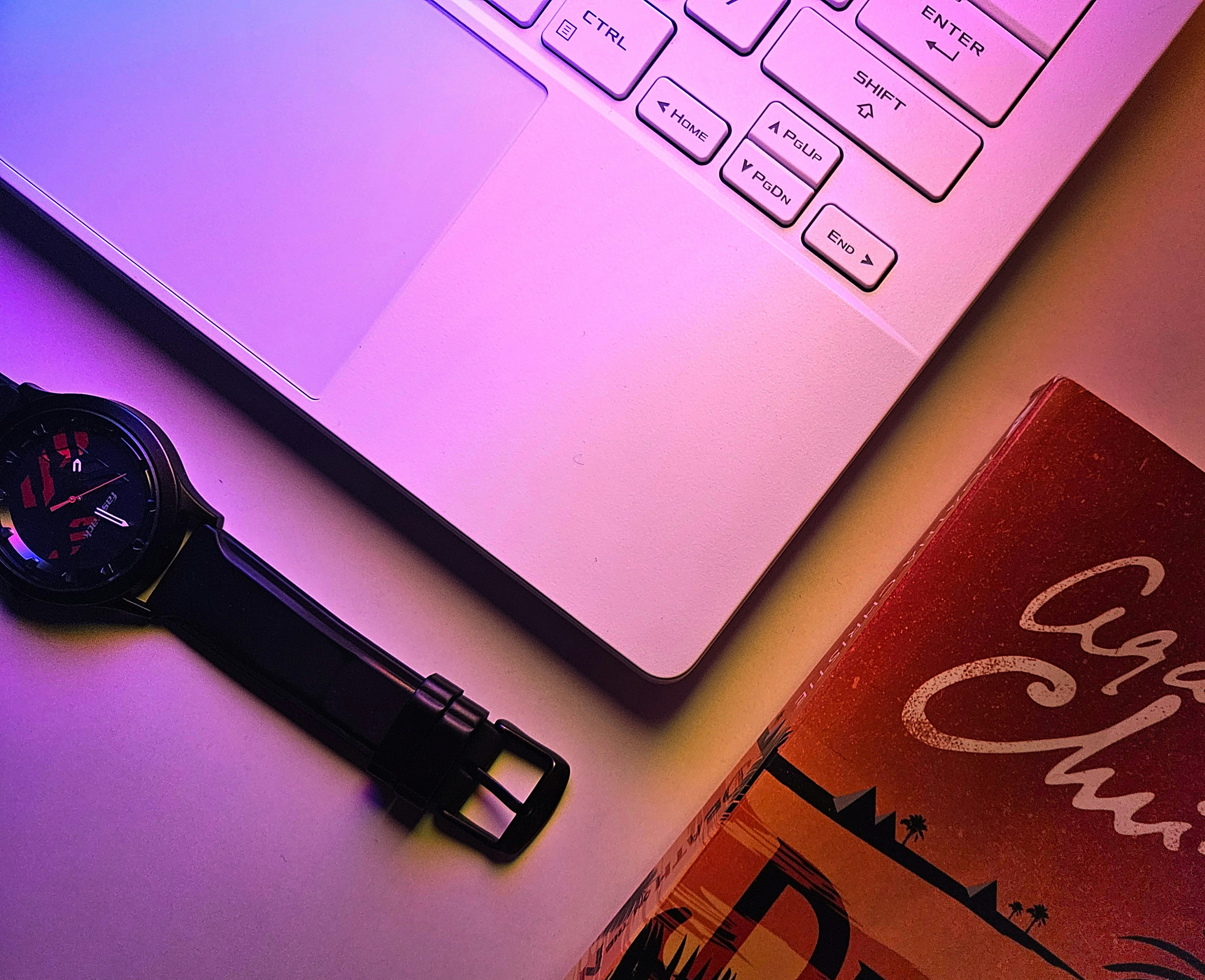Neon-lit Workspace: A Watch, a Laptop Core, and a Worn Diary