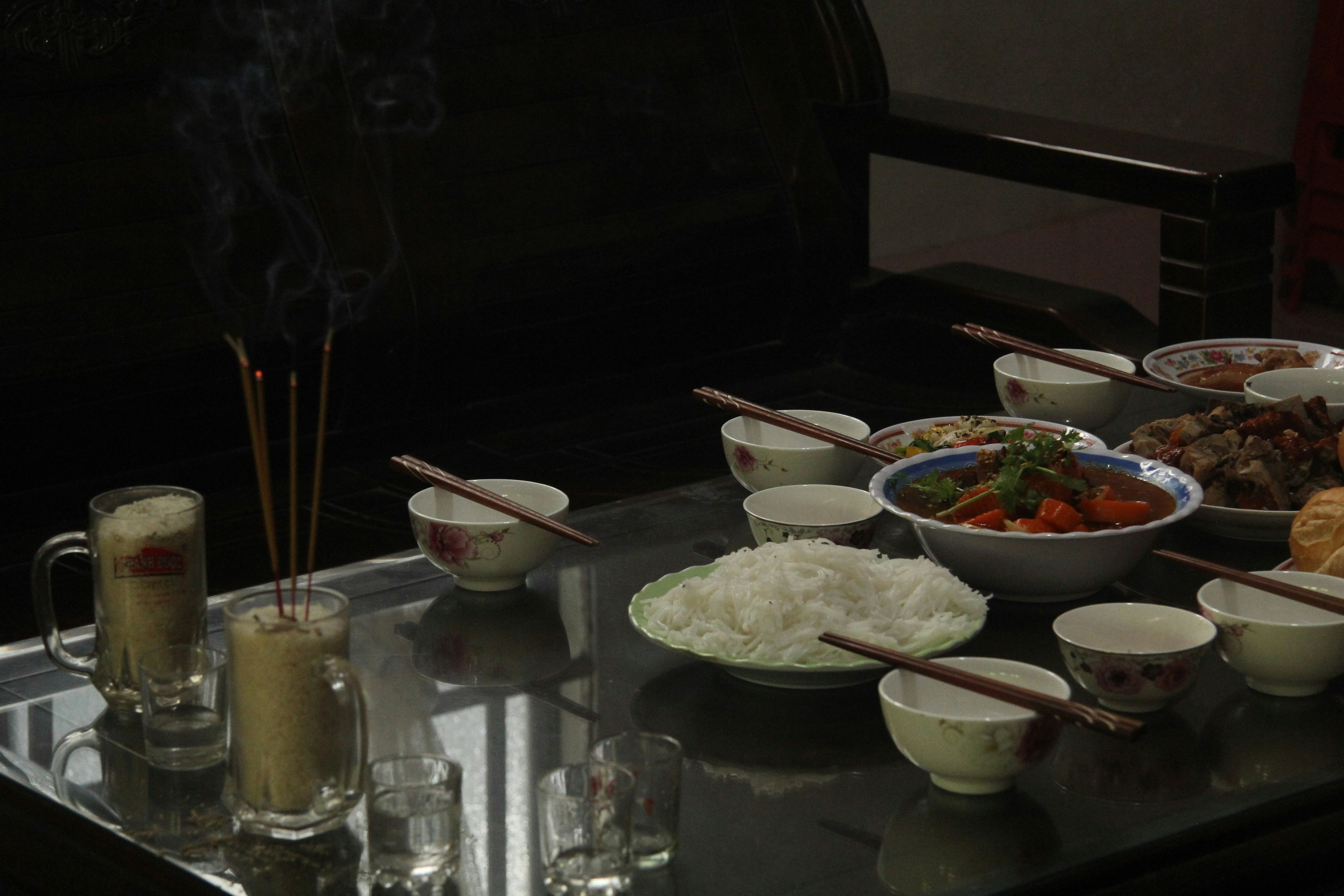 Steam rising over a shared Asian feast on a lacquered dining table