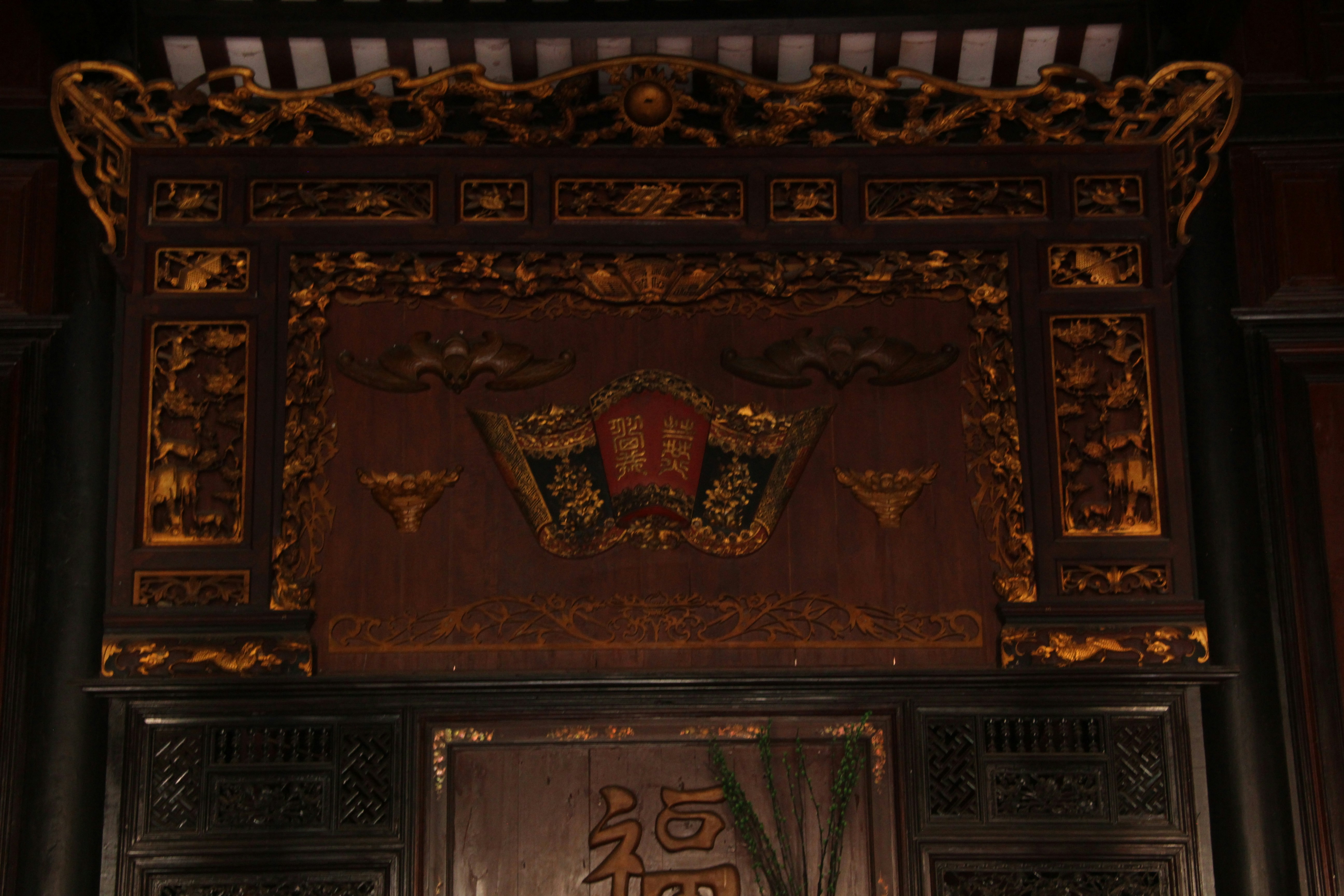 Ornate Temple Carving with Central Emblem and Chinese Character