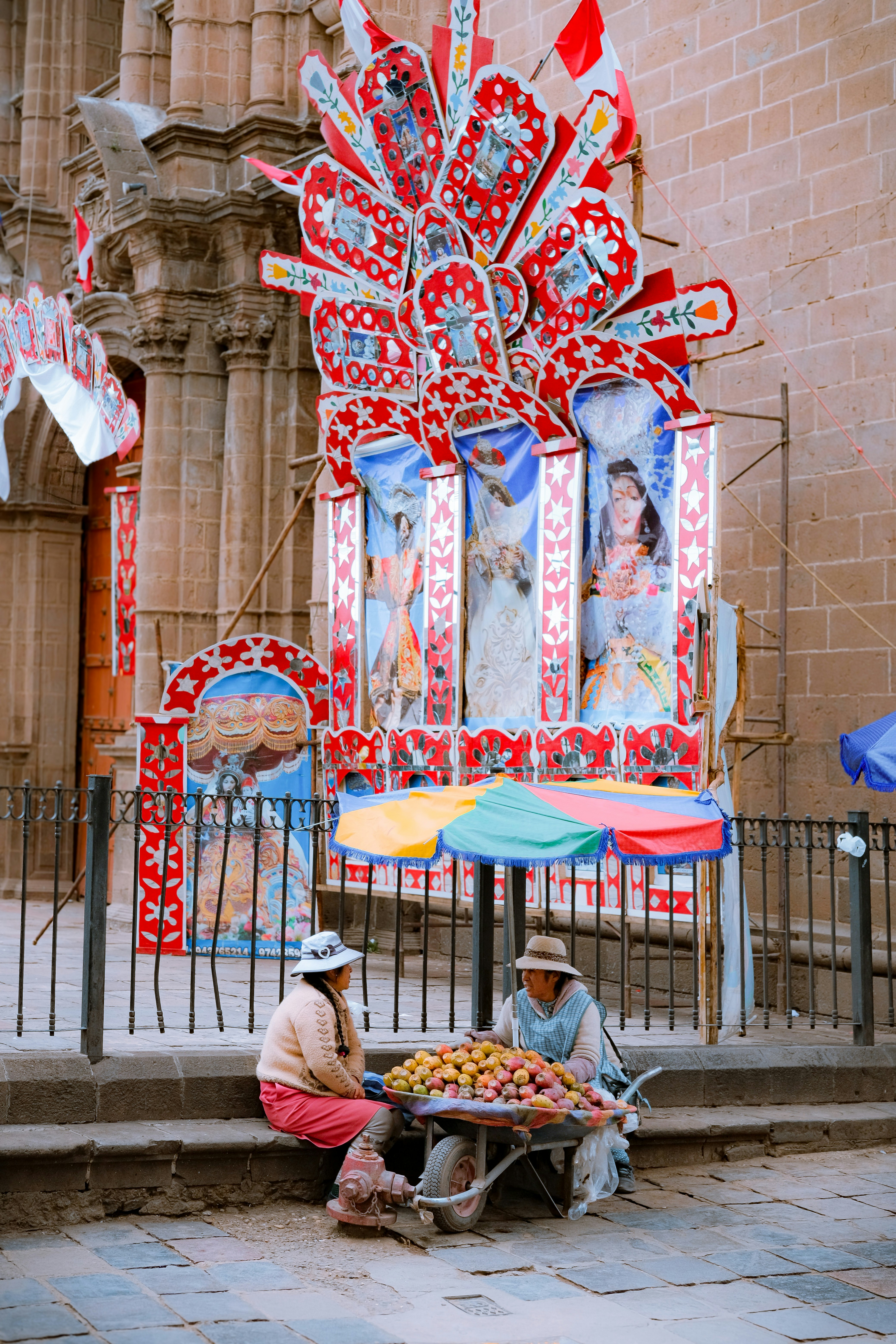 Fruit Carriers Beneath a Colorful Shrine: A Quiet Moment by the Festive Backdrop
