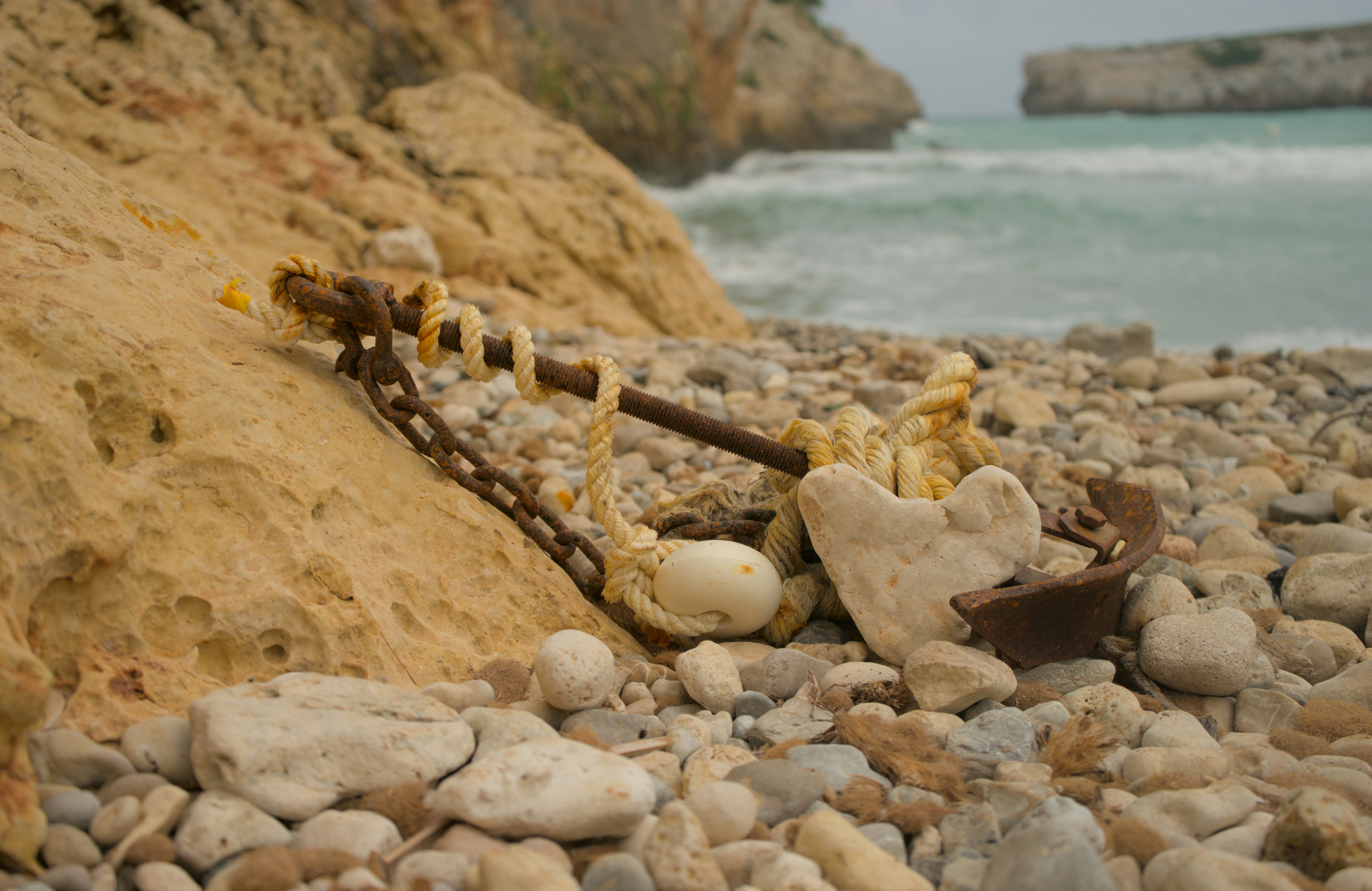 Rusted Chain and Pebble Fossils on a Quiet Cove