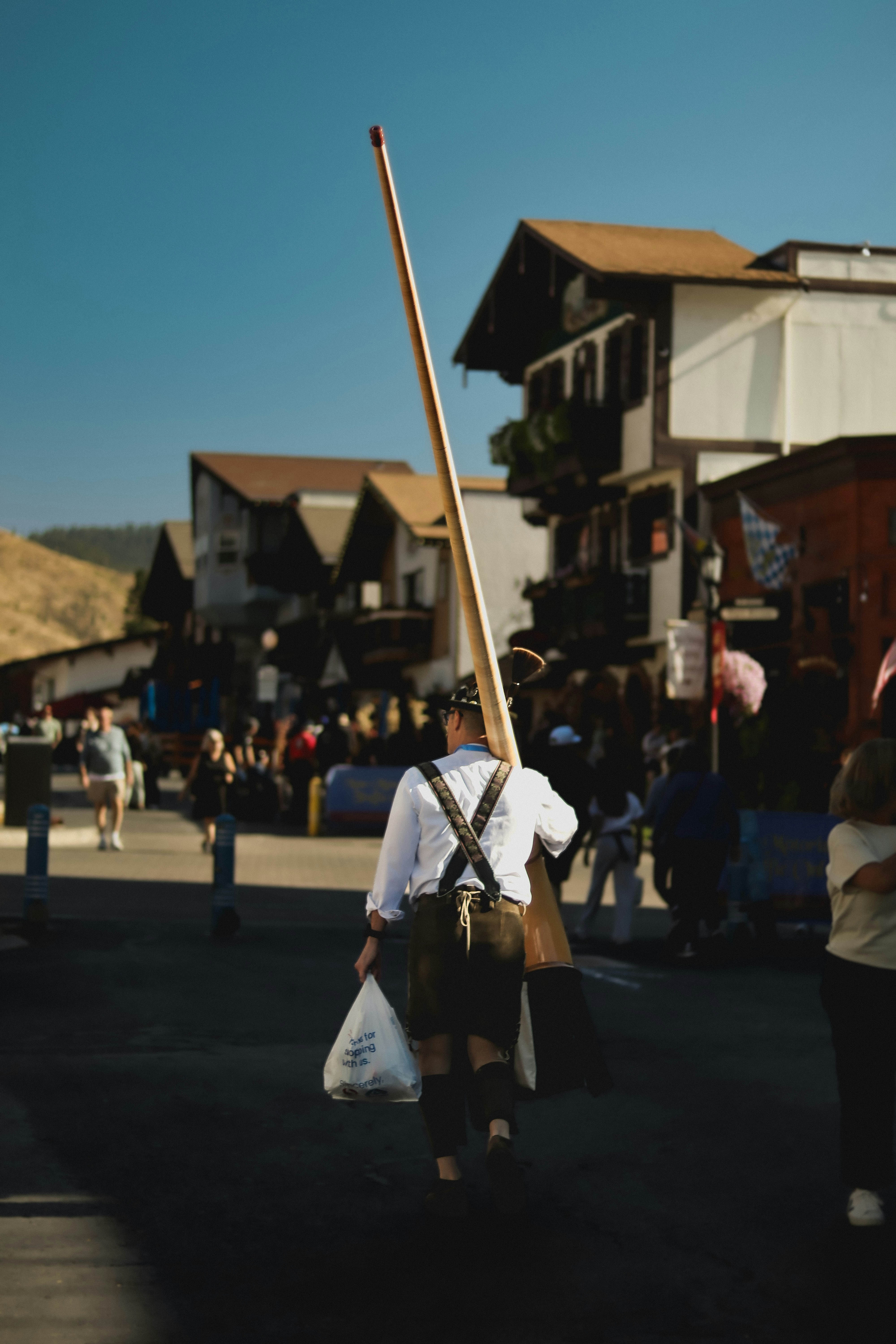 Pole Carrier: A Street Vendor Balancing Tradition and Travel in a Lantern-lit Avenue