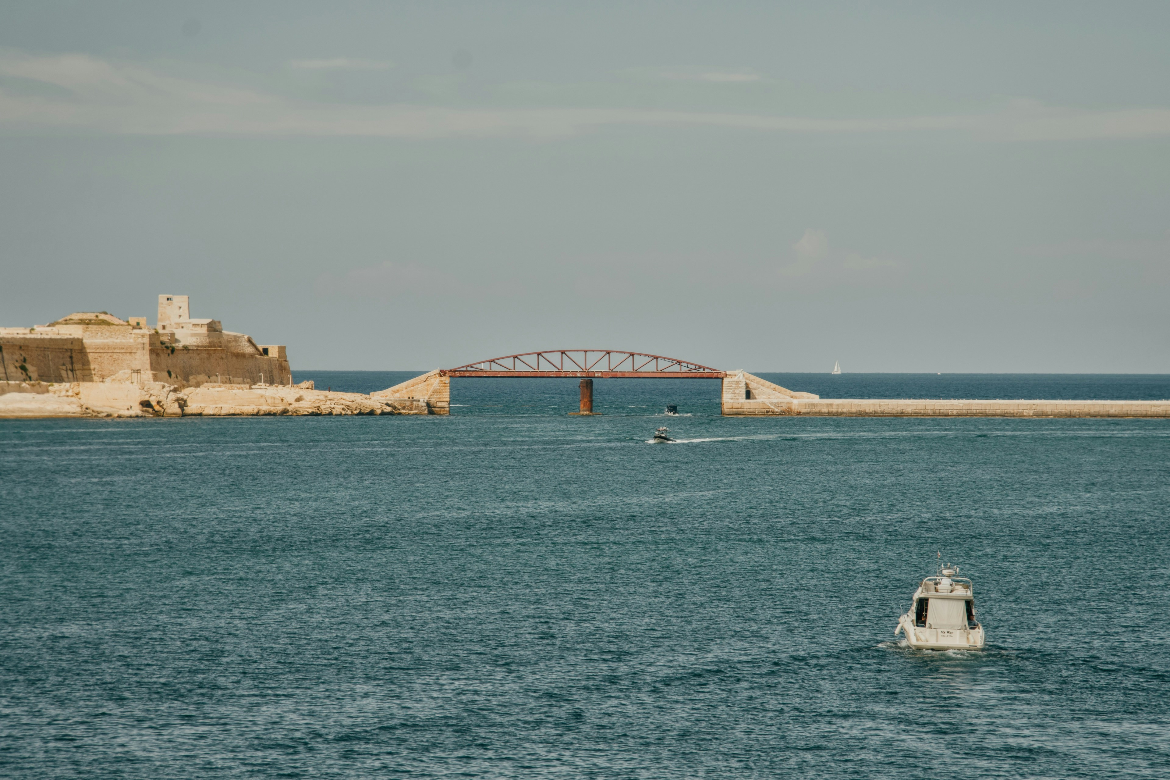 Harbor Span: A Boat, the Sea, and a Distant Fortress