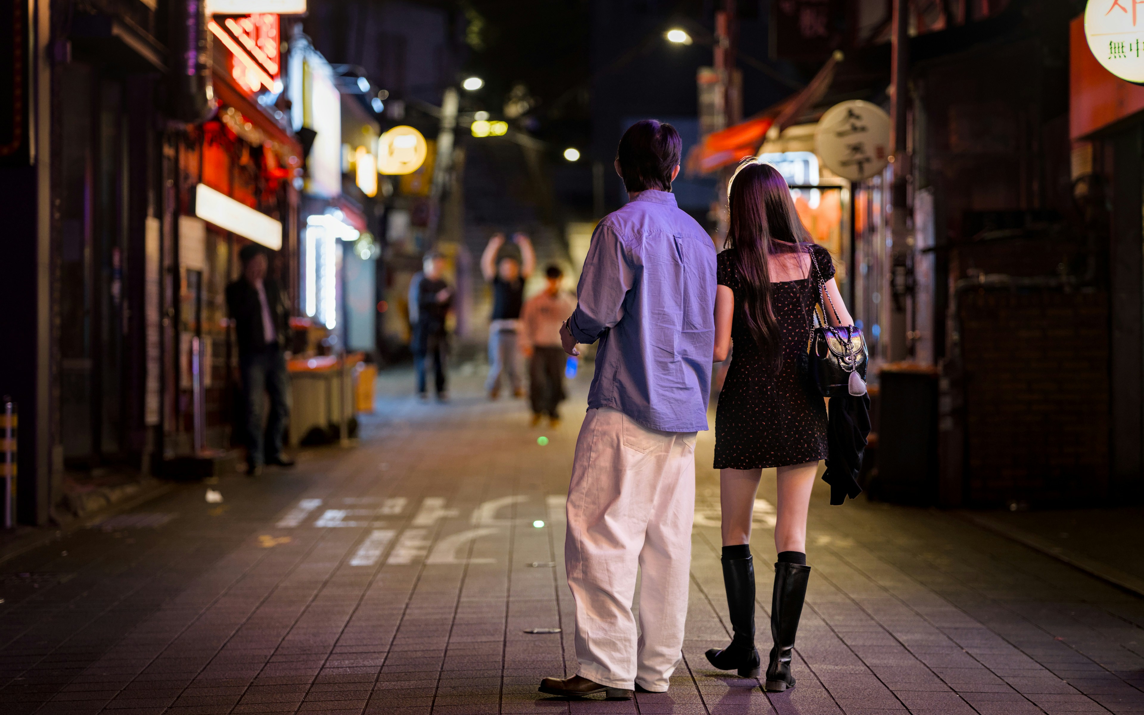 Night Walkers in Neon: A Quiet Moment in a Lively Street