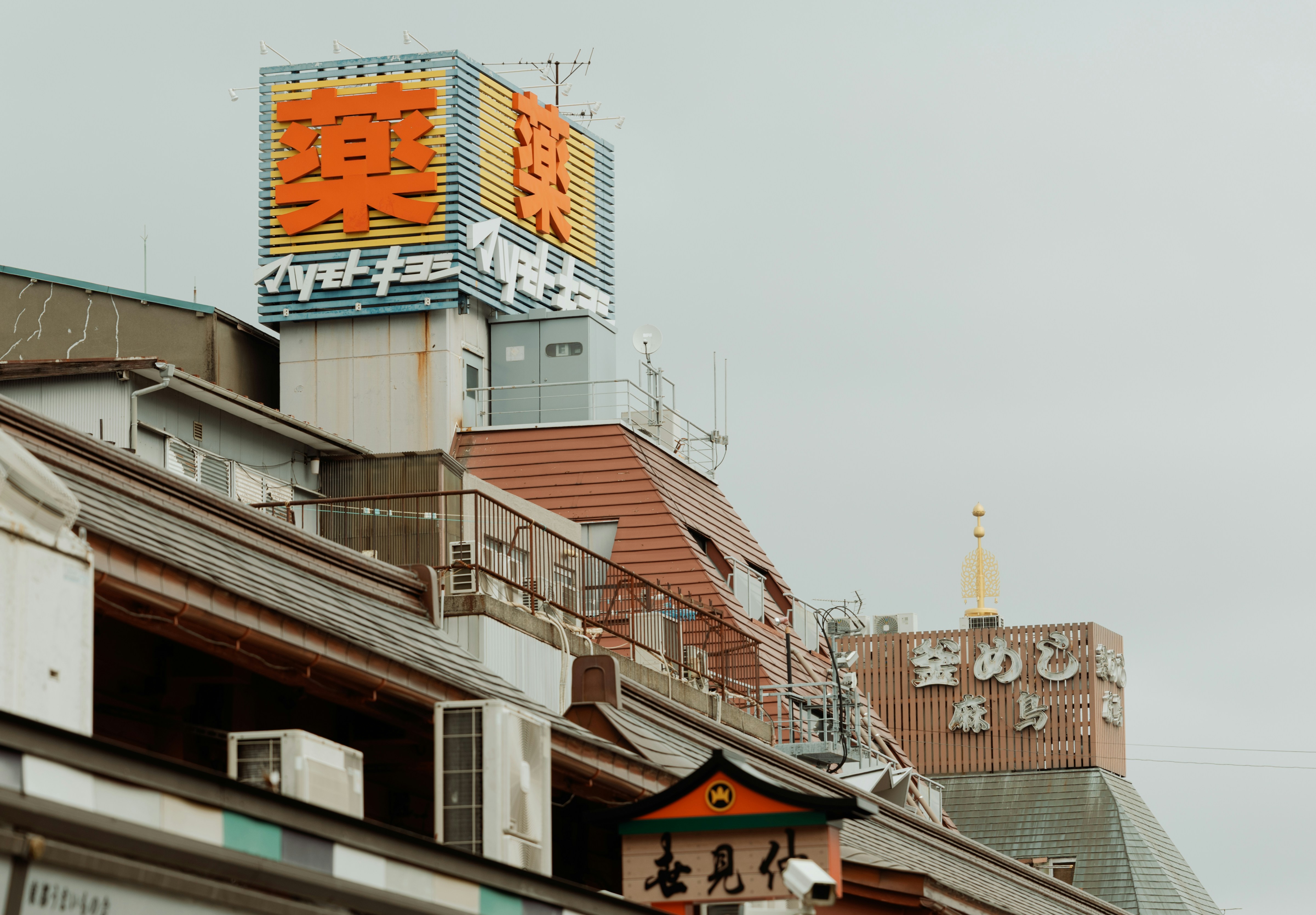 Roofline Signals: Neon Pharmacy Signover Over a Japanese Street