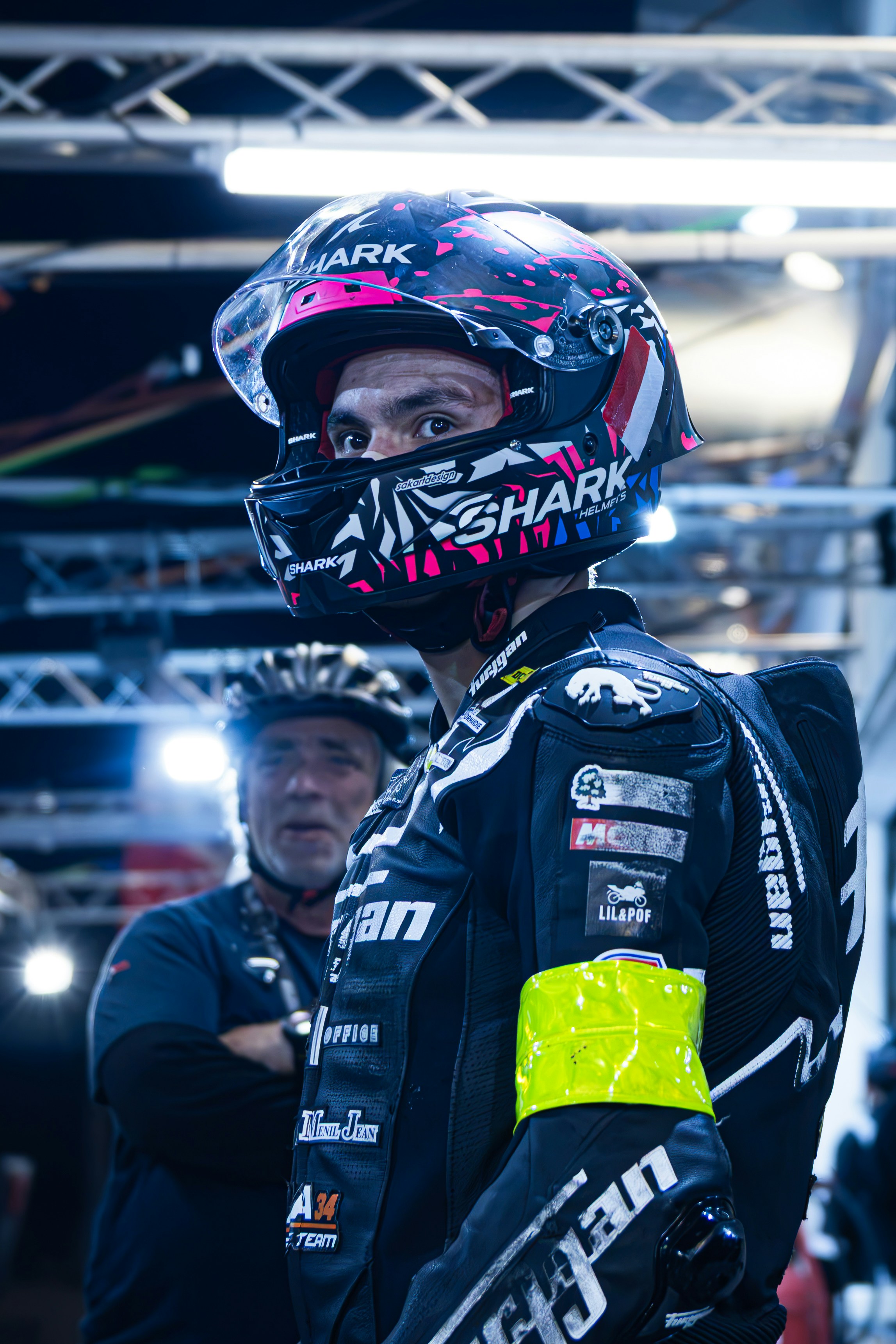 Helmeted Rider in Pit Lights: Focused Gaze in a Neon-Accented Pit