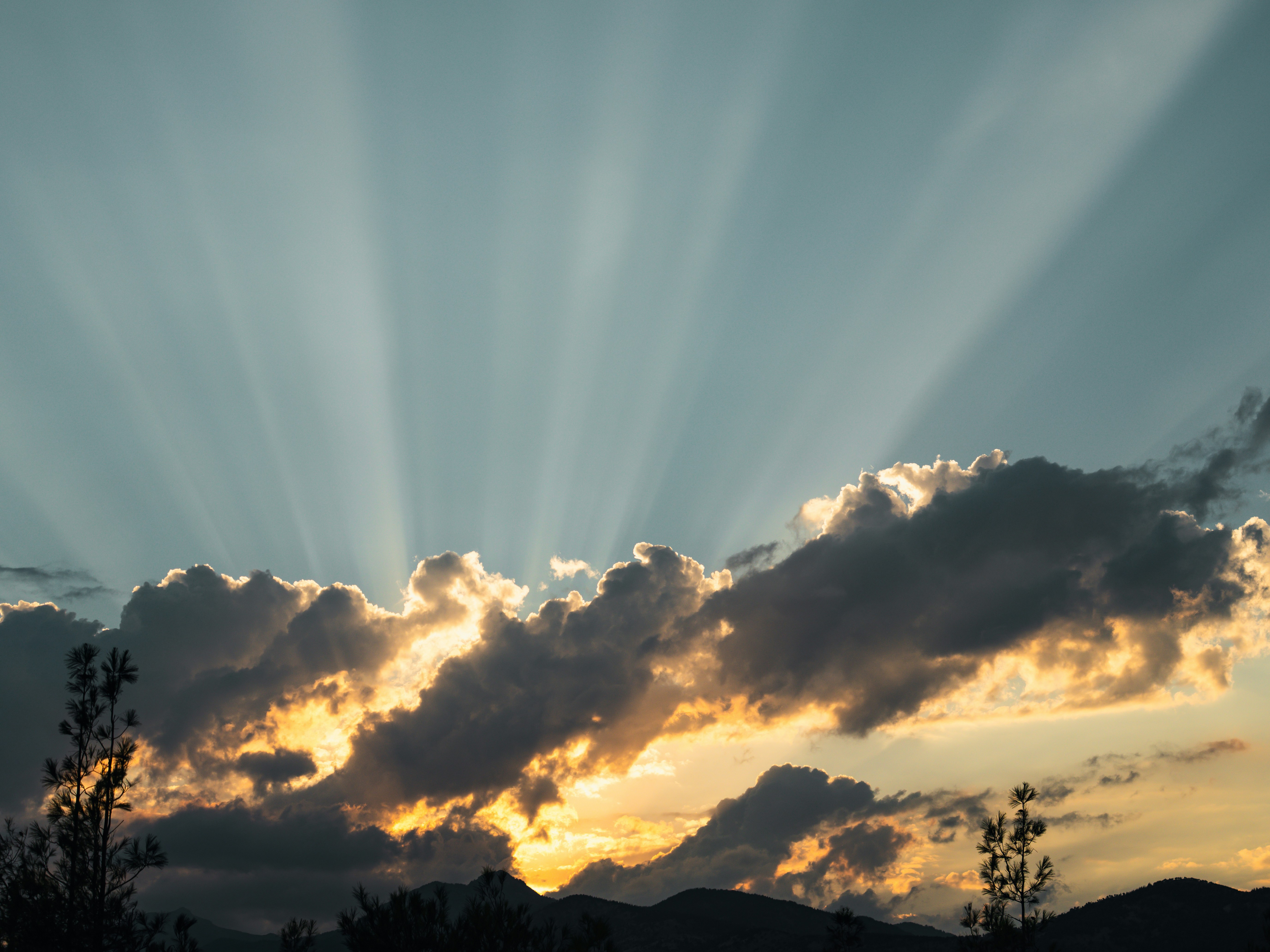 Sunlit Break: Rays Crown a Cloudscape Over Quiet Terrain