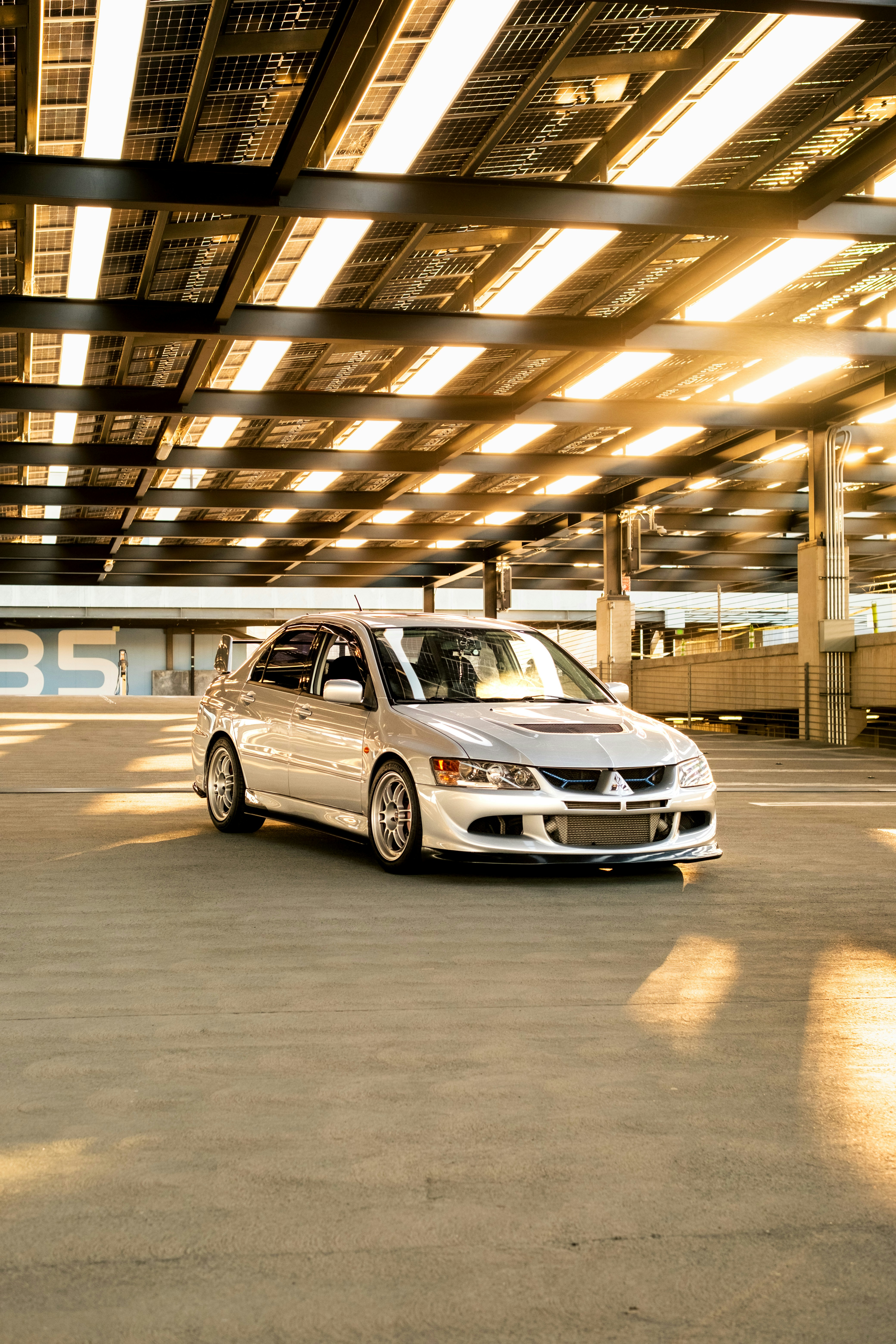 Silver Mitsubishi Lancer in a Golden Hour Parking Garage