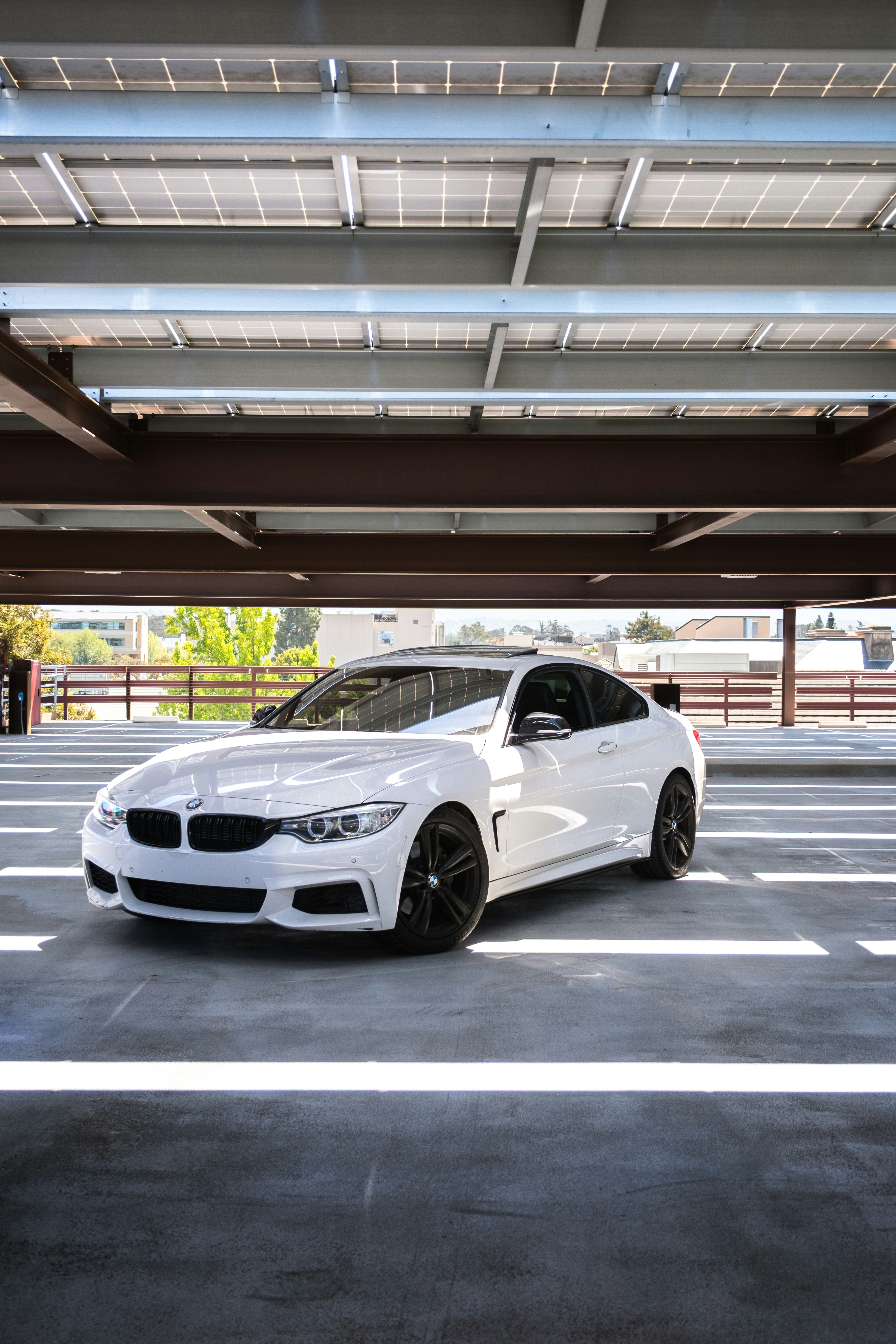 White BMW under a sunlit parking structure