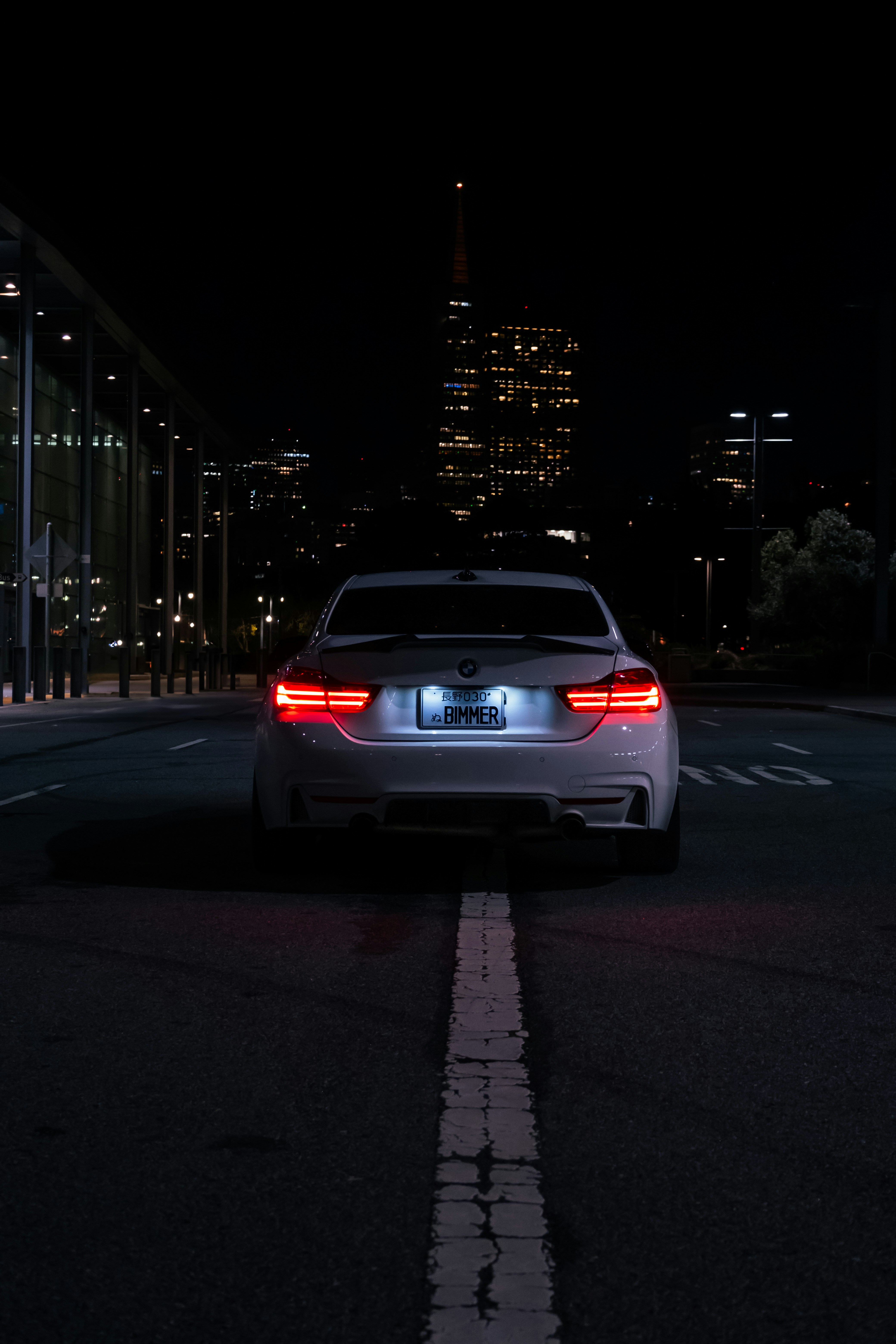 Night Drive: The BMW’s Taillights Converge on a City Skyline