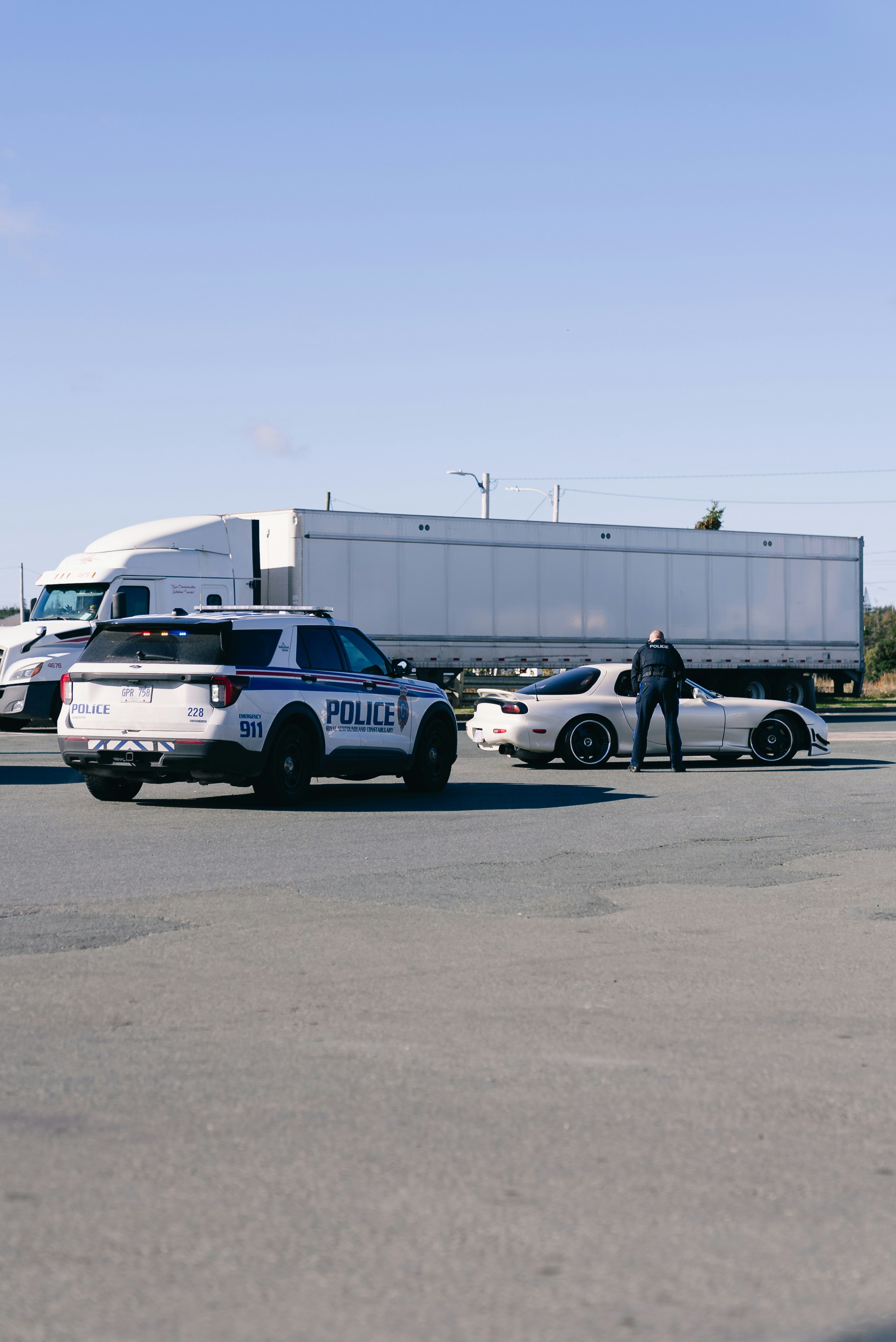 Stalled Street Scene: Police Presence by a Semi-Truck and Racer Car