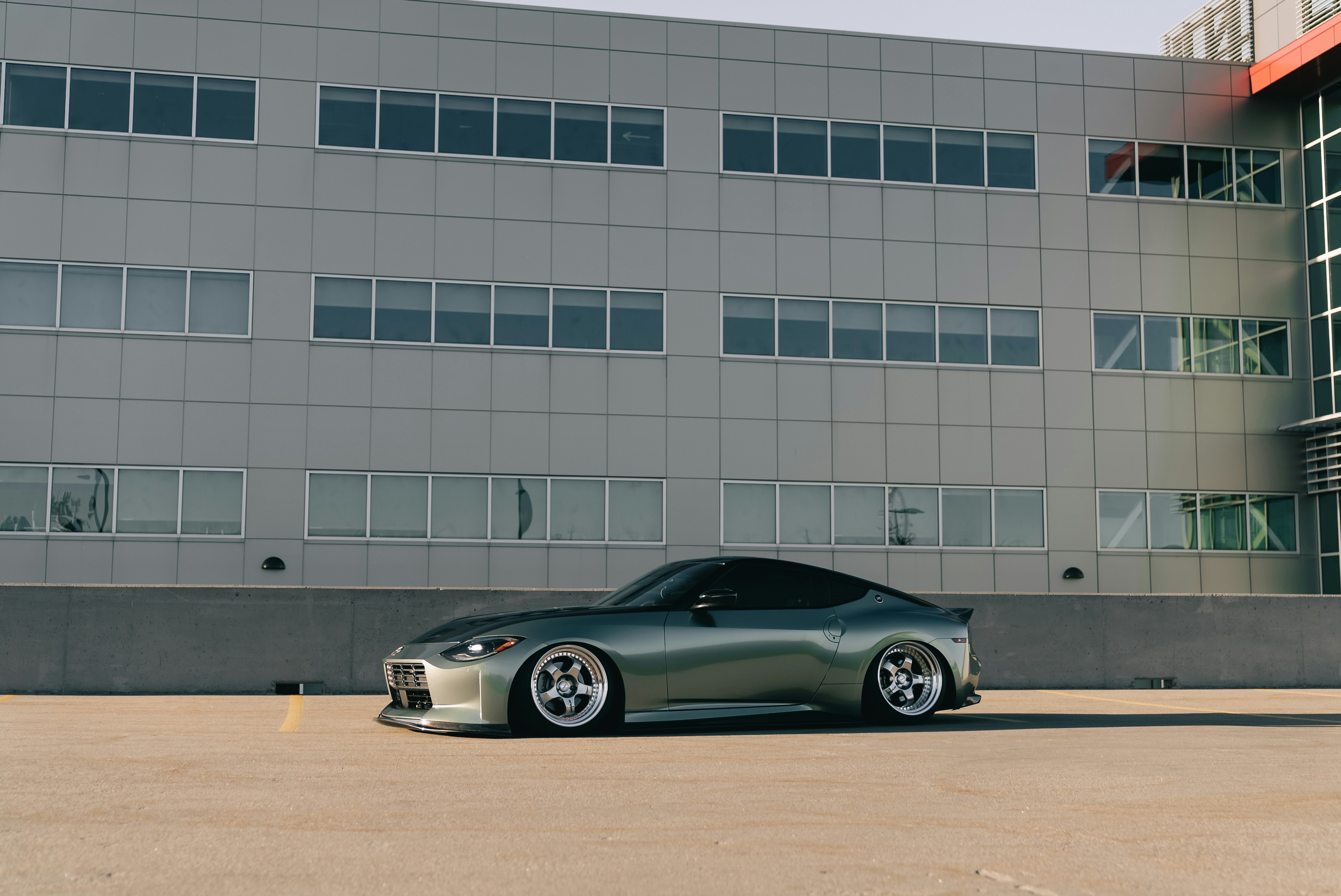 Low-slung silver sports coupe resting in an empty rooftop parking lot
