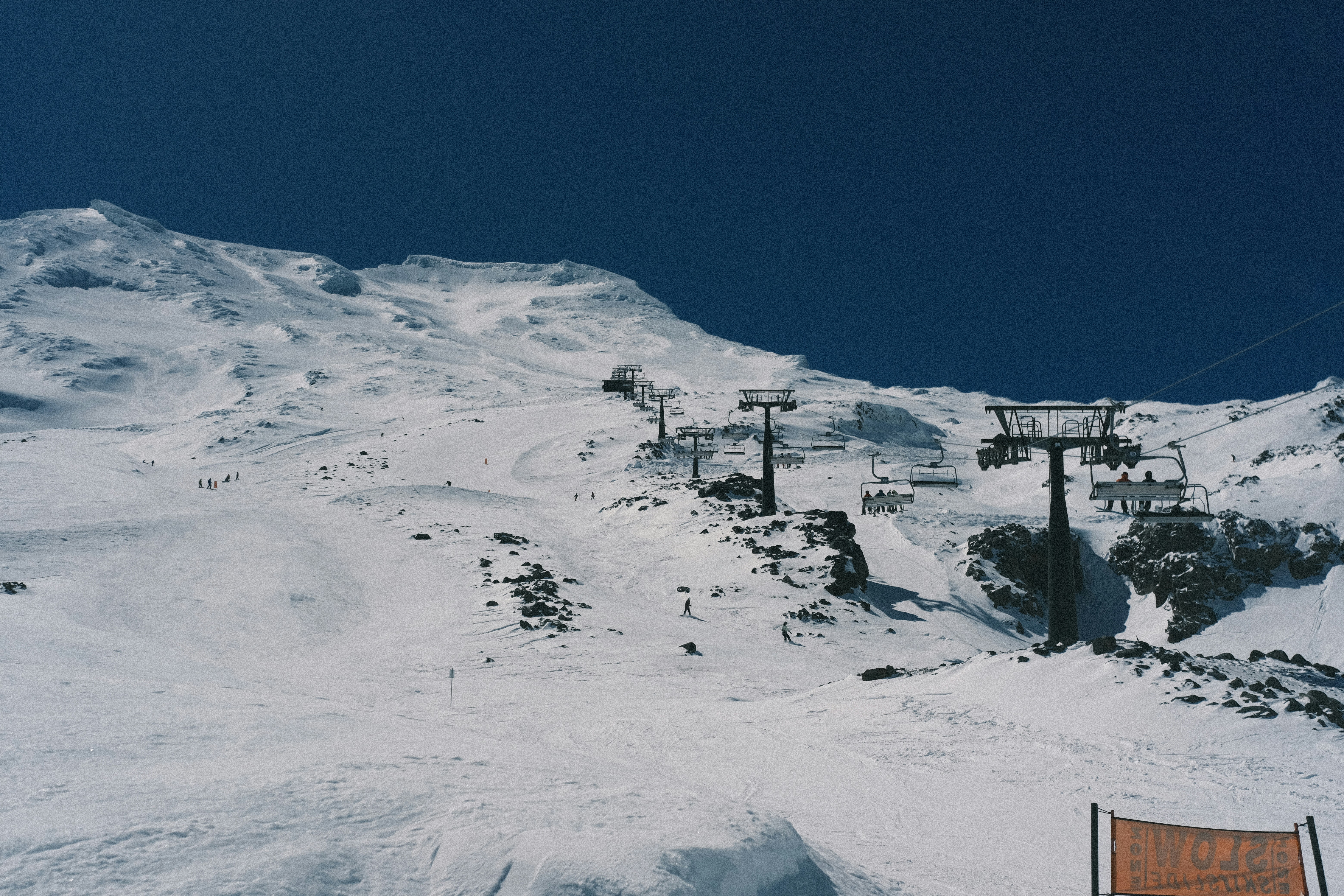 Snow Glide under a Clear Blue: Chairlift Shadows Across the Slopes