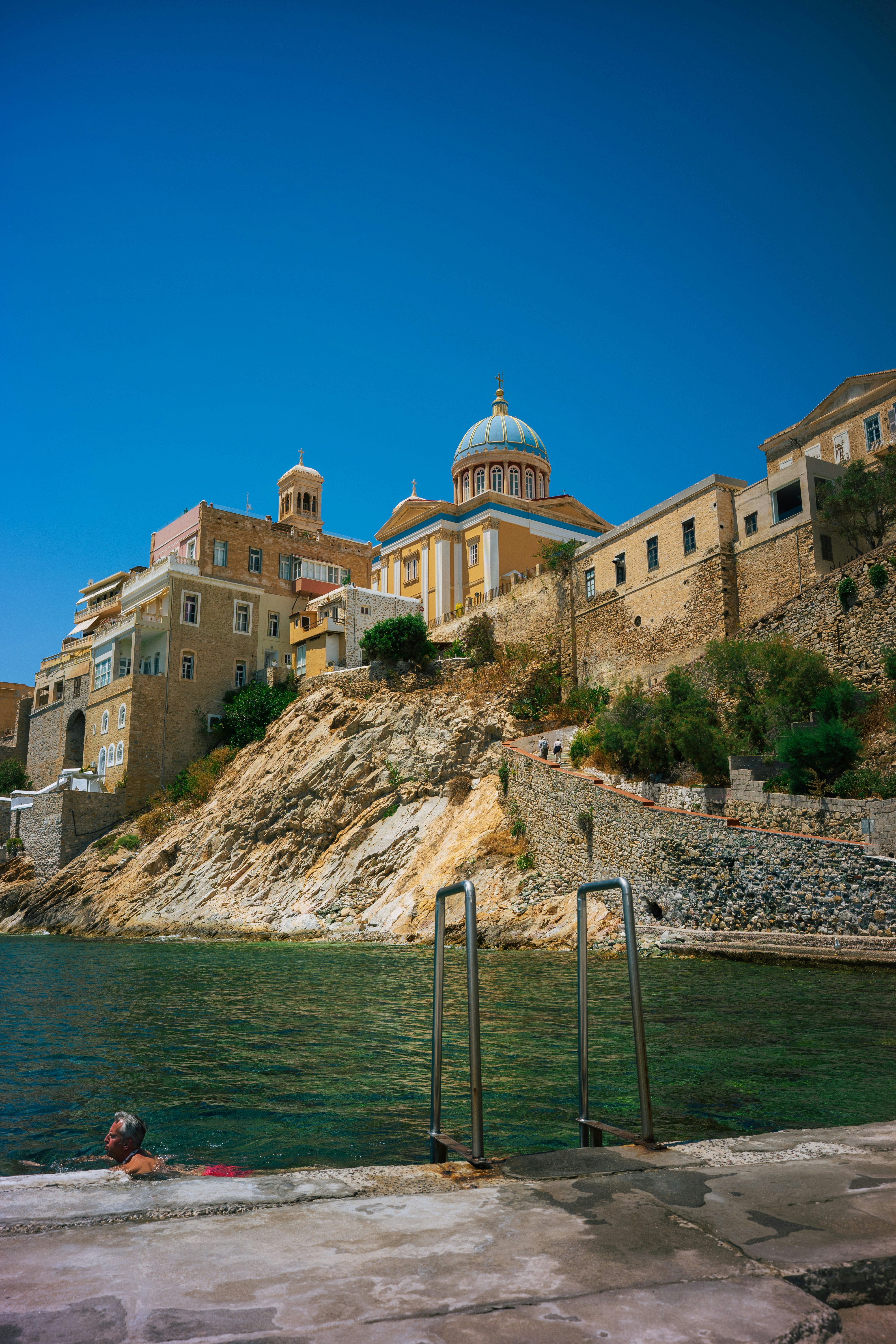 Harbor fortress: cliffside buildings and blue-domed church against a vivid sky
