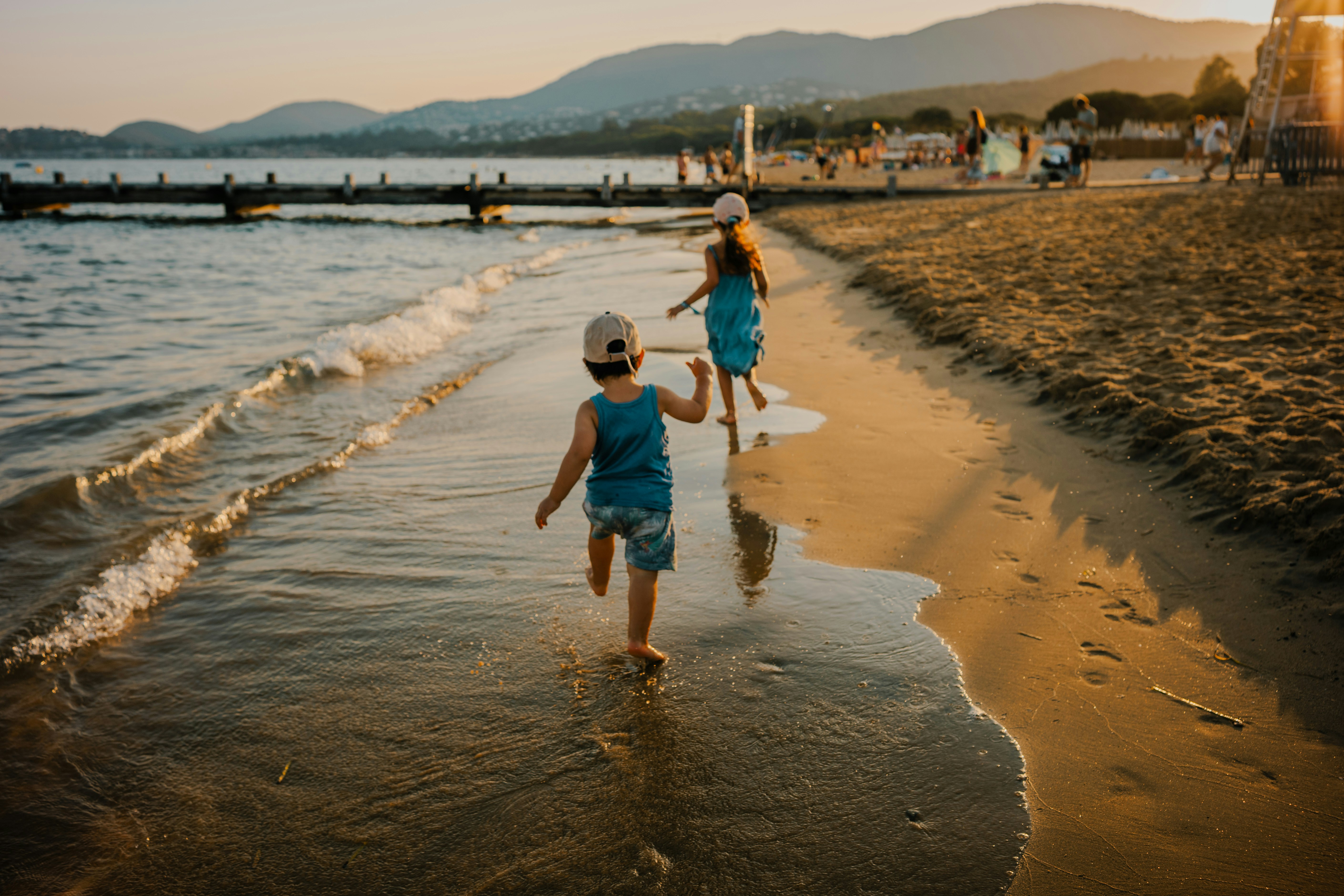 Sunlit Footsteps: Two Children Chase the Tides Along a Golden Beach
