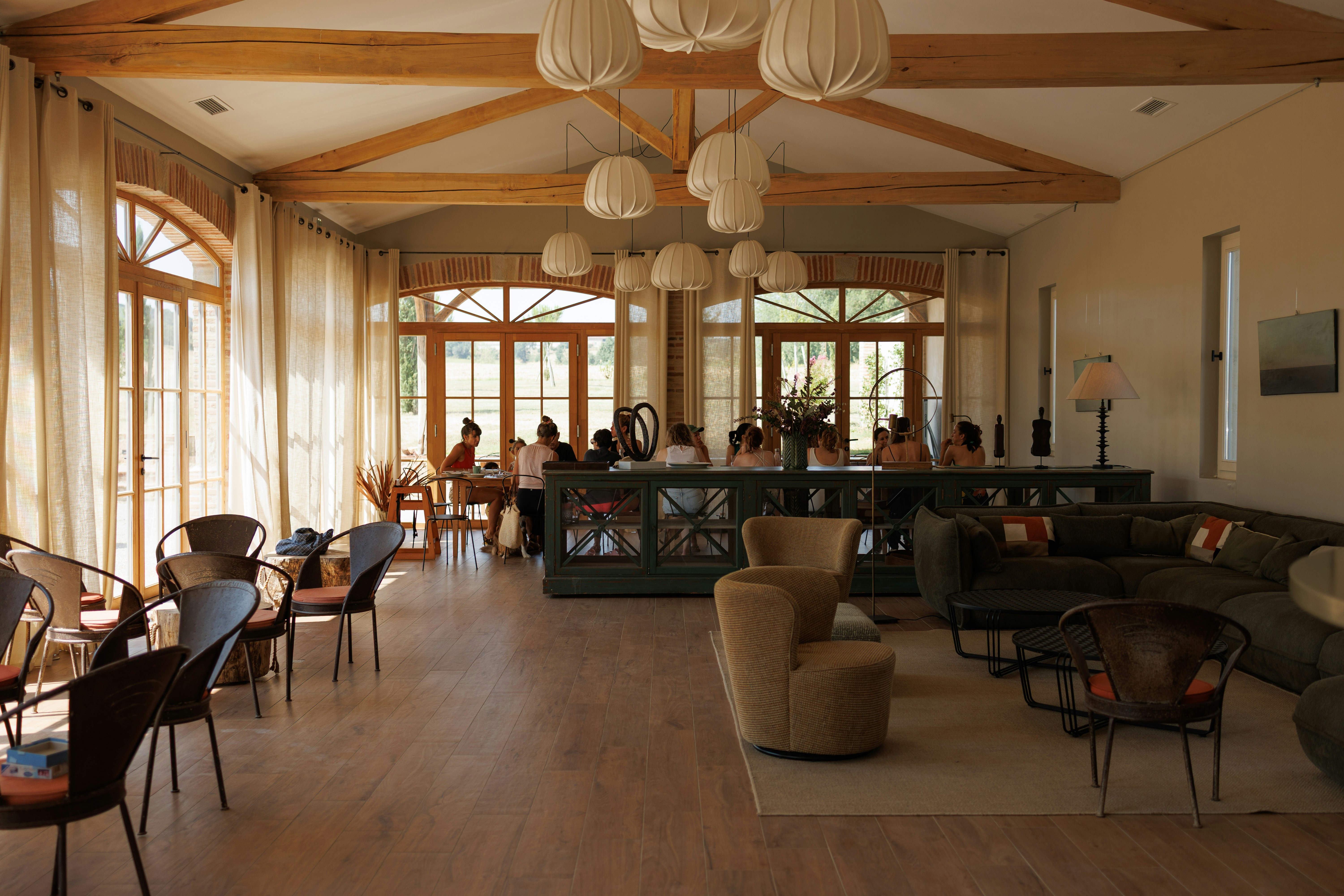Sunlit Hotel Lounge with Social Gathering under Curved Glass Windows
