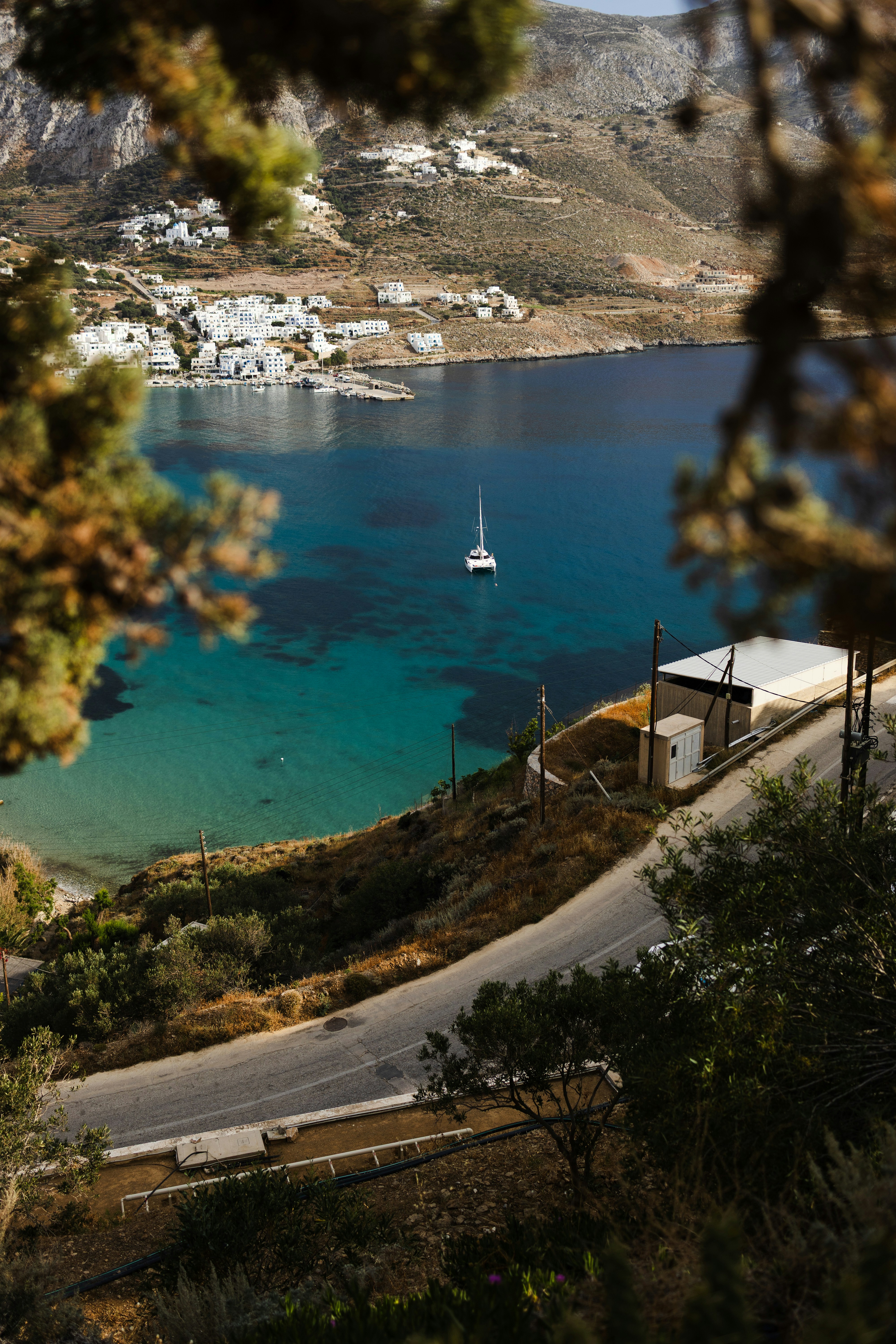 Harbor at Dusk: A Sailboat in Turquoise Waters Framed by Cliffside Village