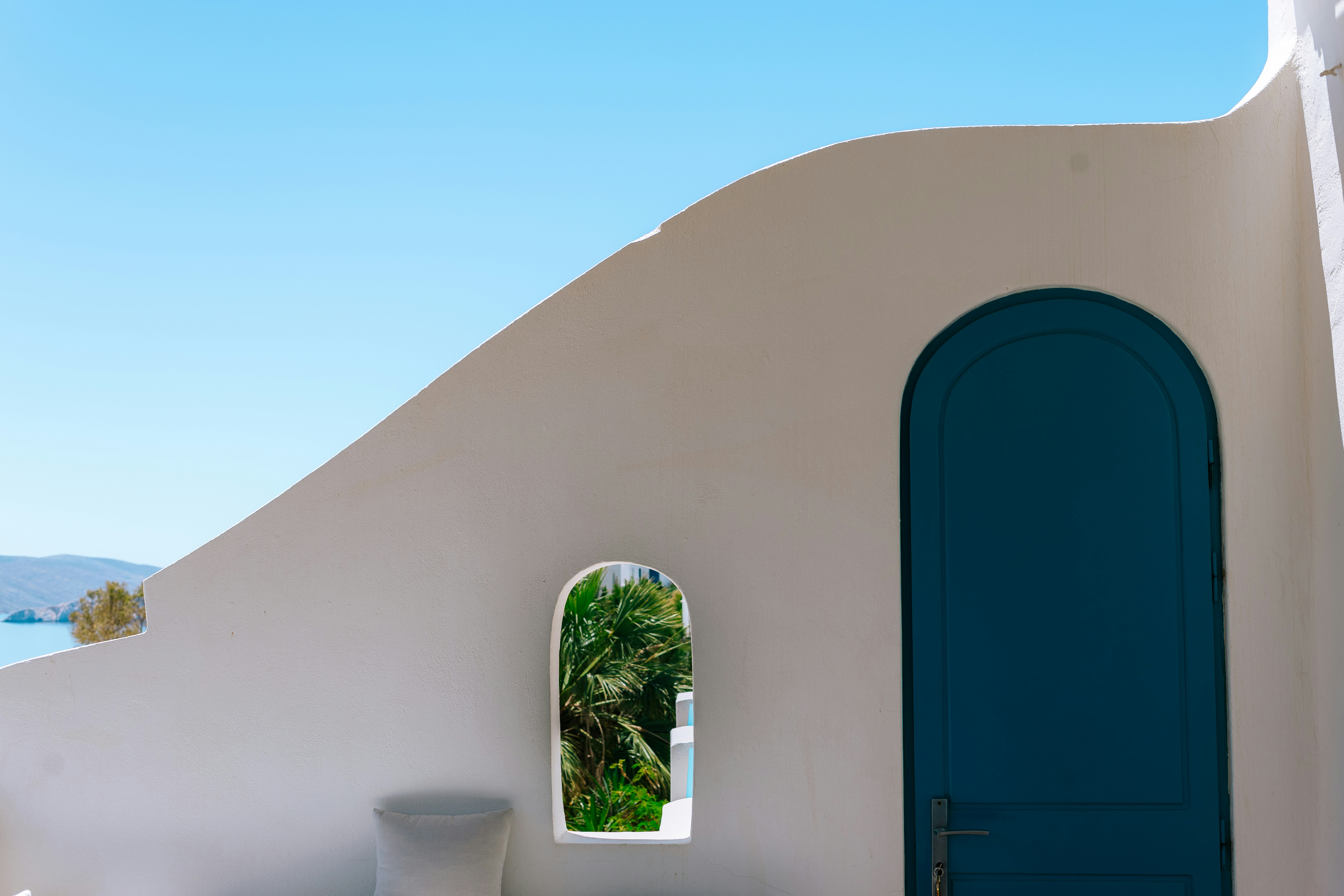 Whitewashed Wall, Teal Door, and Serene Archway Under a Clear Blue Sky