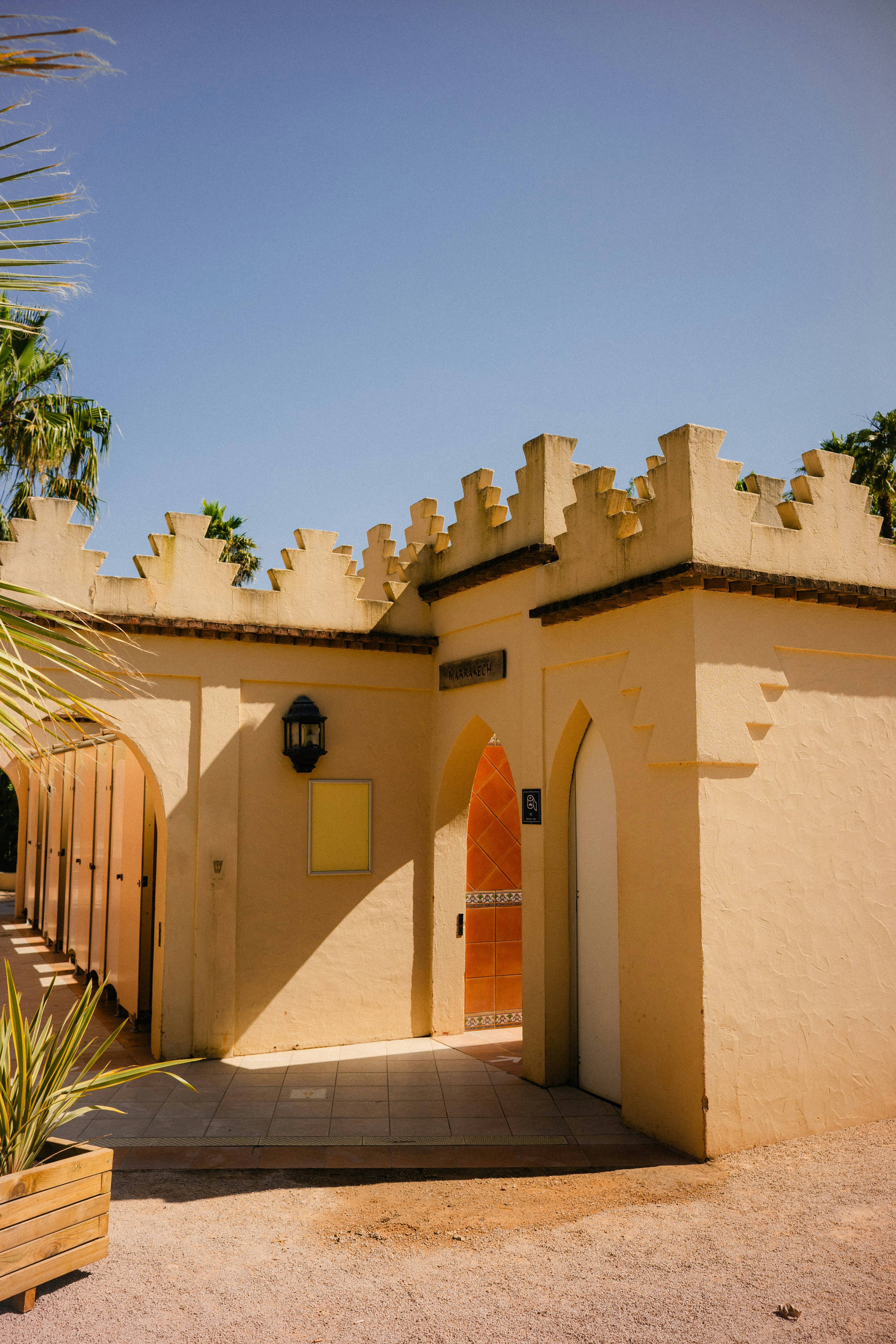 Sunlit Moorish Façade: Terracotta Door Under Castellated Roofline