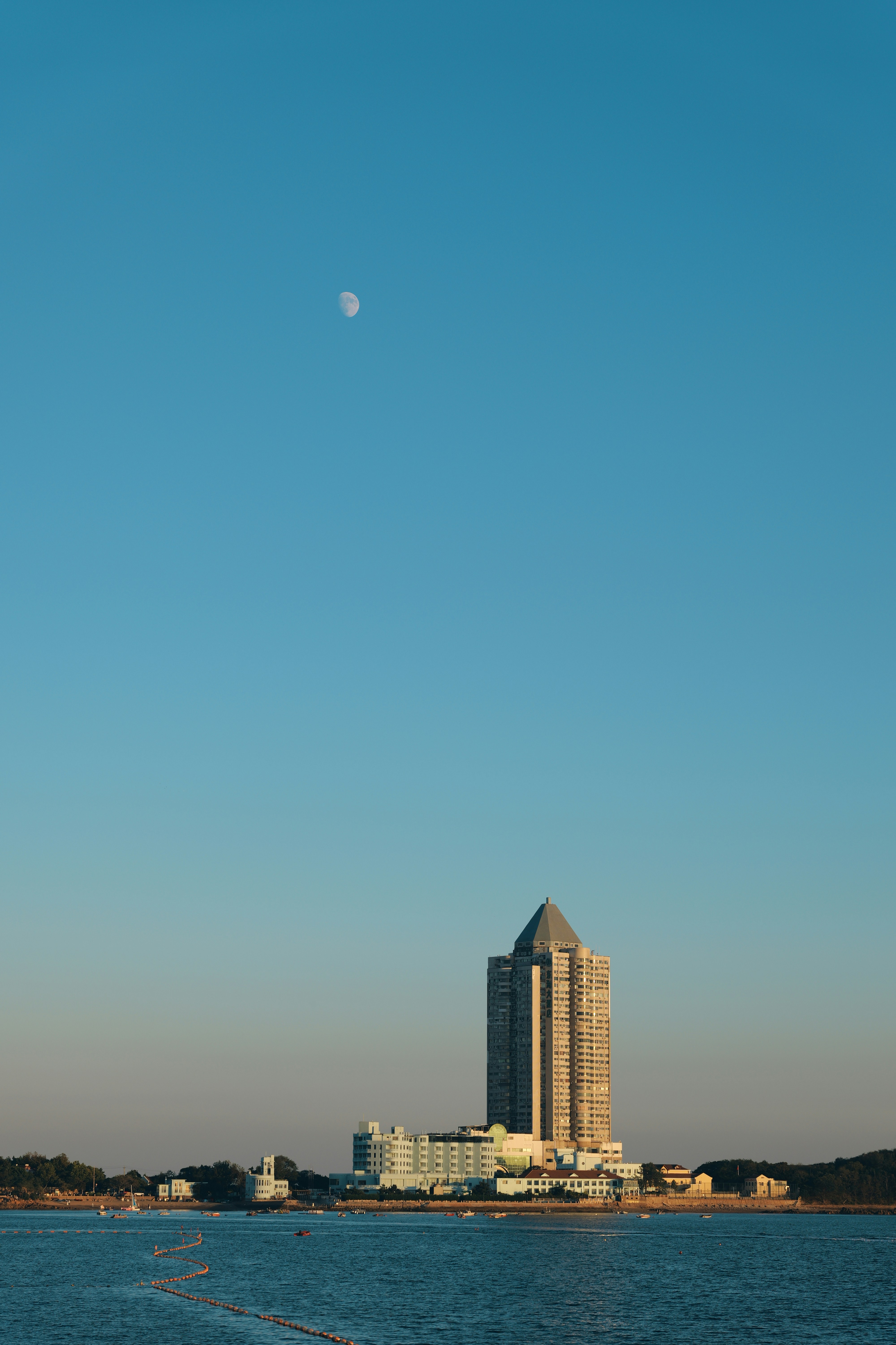 Coastal City Far at Dusk: A Tower Breathing Light Over Quiet Waters