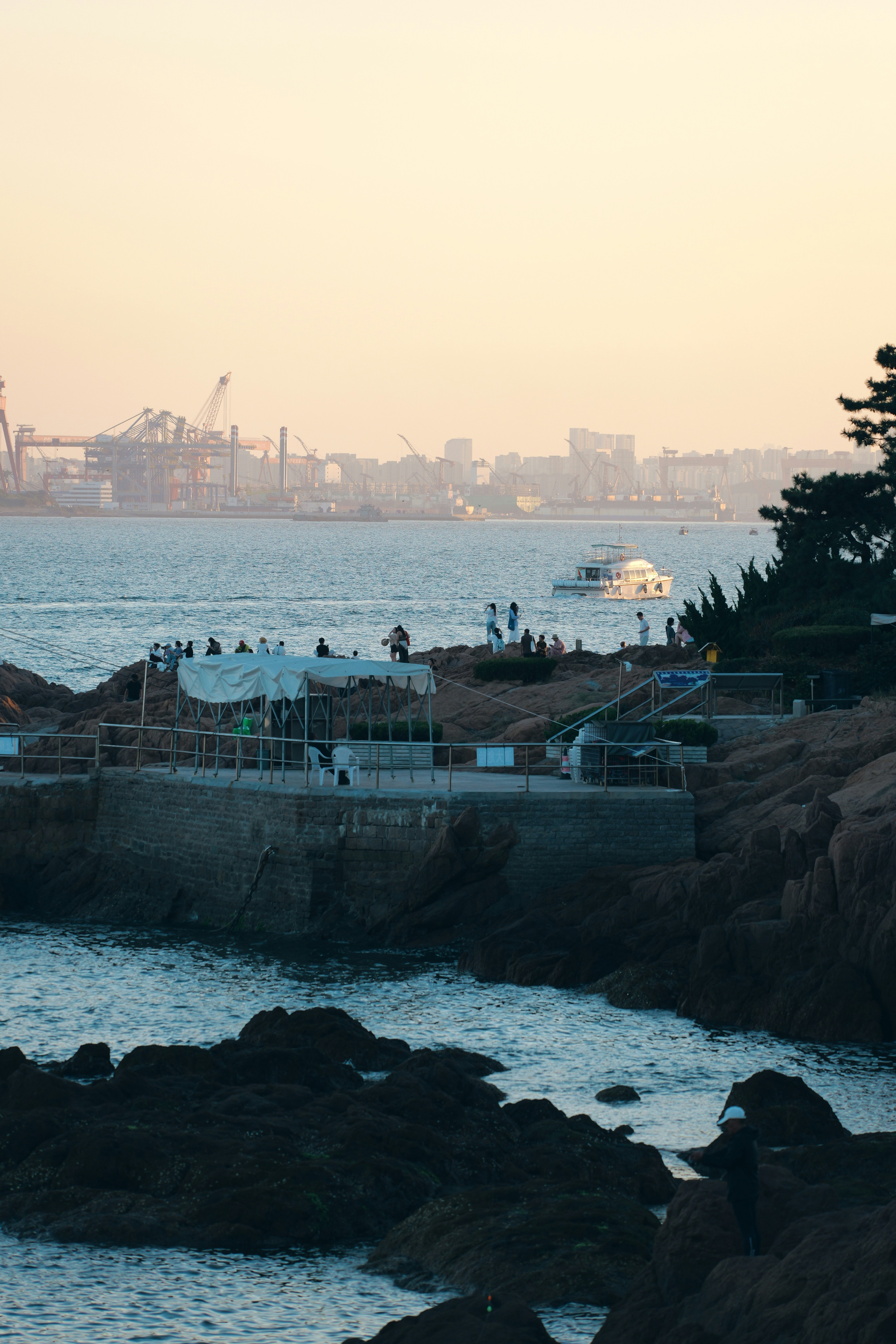 Harbor Gatherings at Dusk: People, Promenade and Boat Beyond the Rocks
