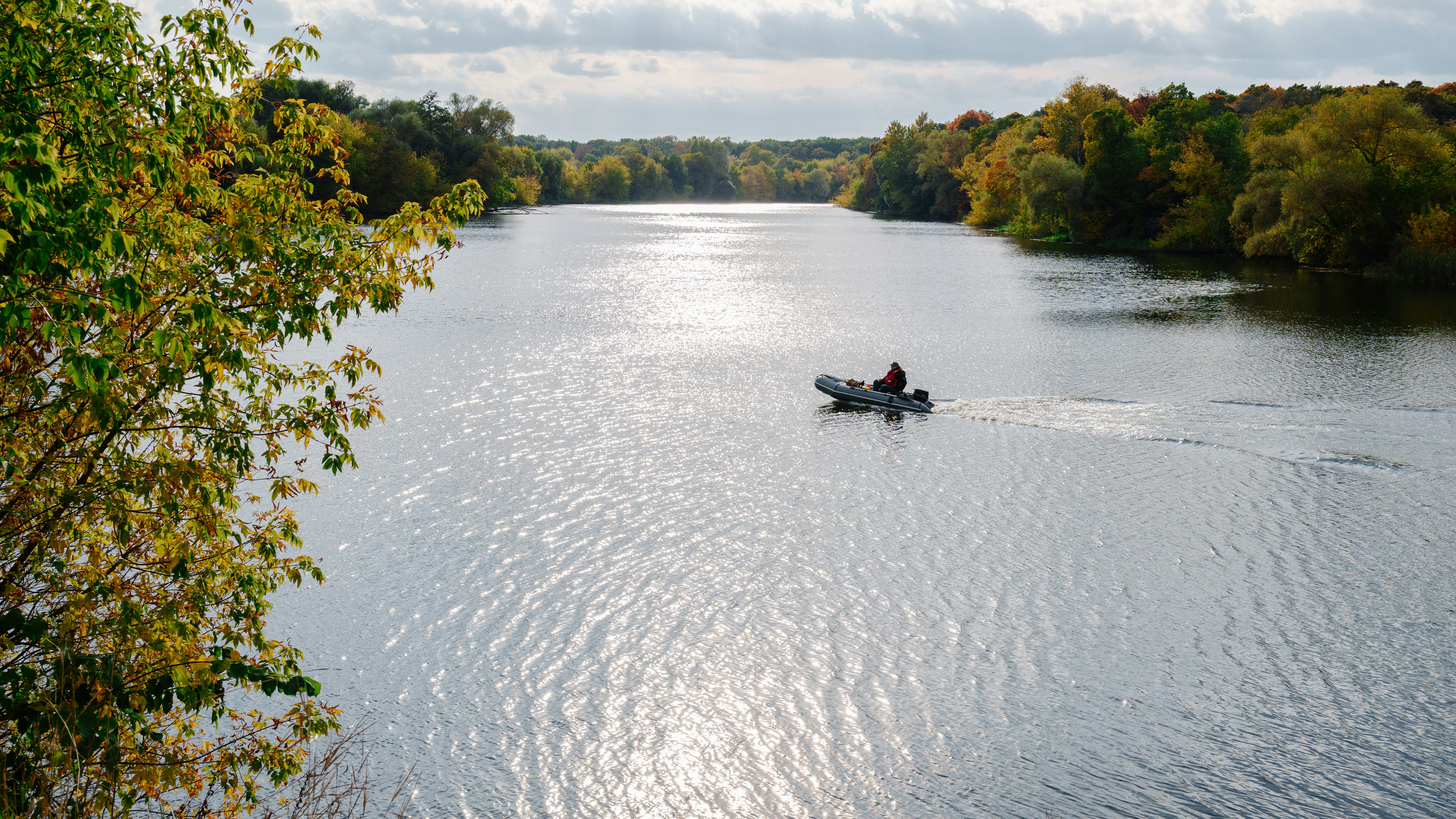 River Run: A lone boat gliding along a sunlit autumn stretch