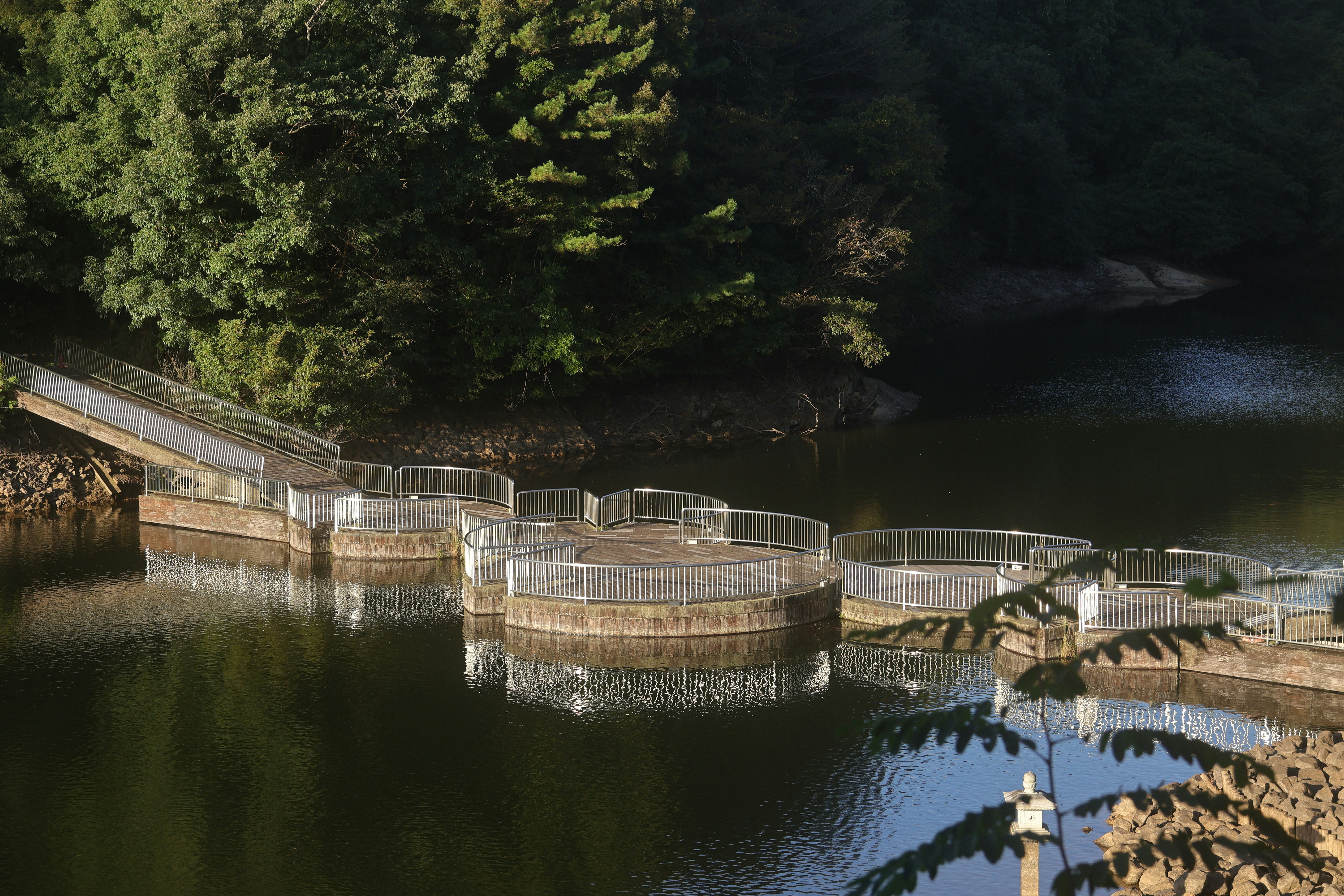 Curved Dam Walkway Across Quiet River