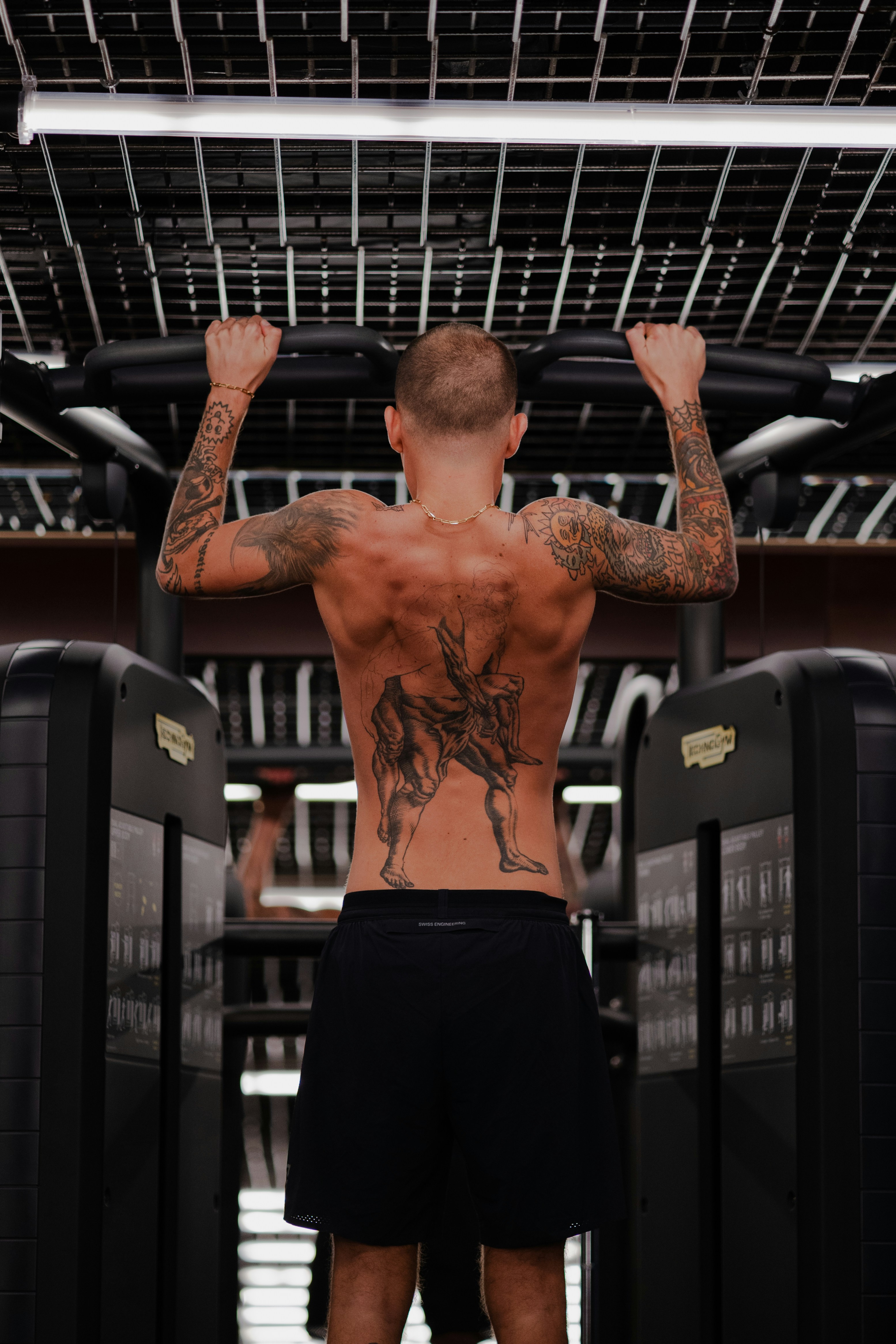Tattooed Strength: Back Shoulder Pull in a Gym Frame