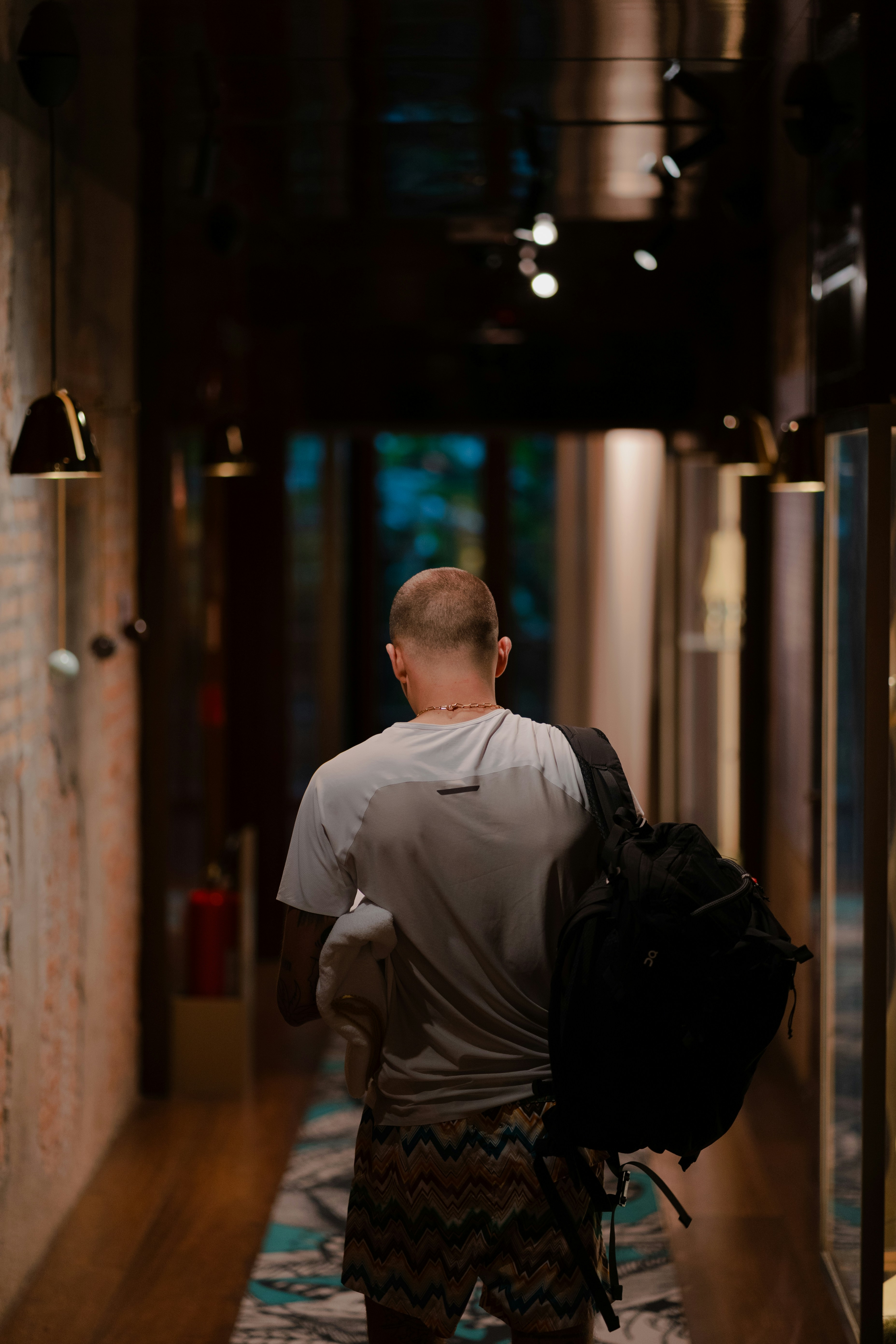 Backpacker in a Neon-lit Corridor: A Quiet Exit from the Hall