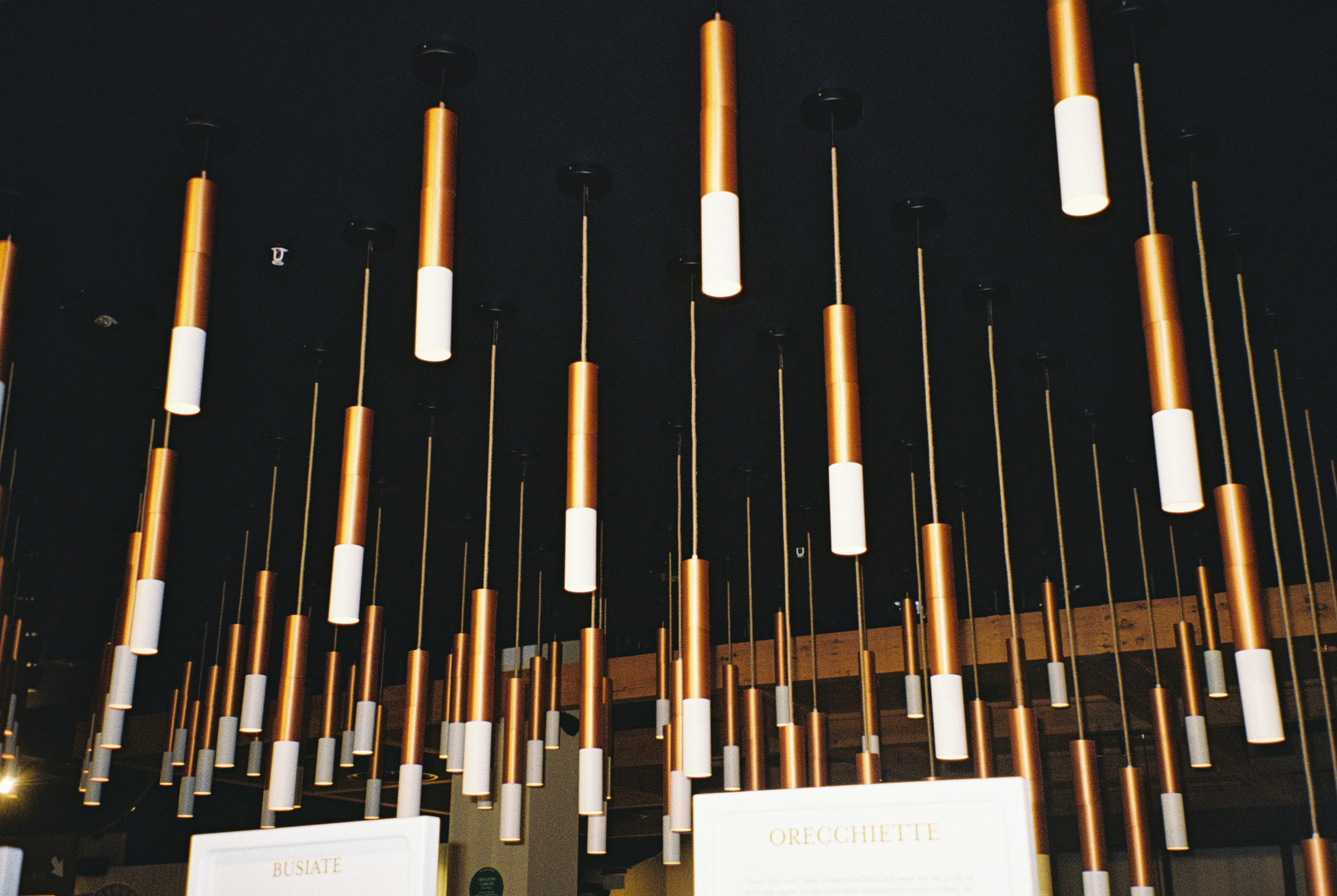 Hanging lampscape: copper cylinders reaching toward a midnight ceiling