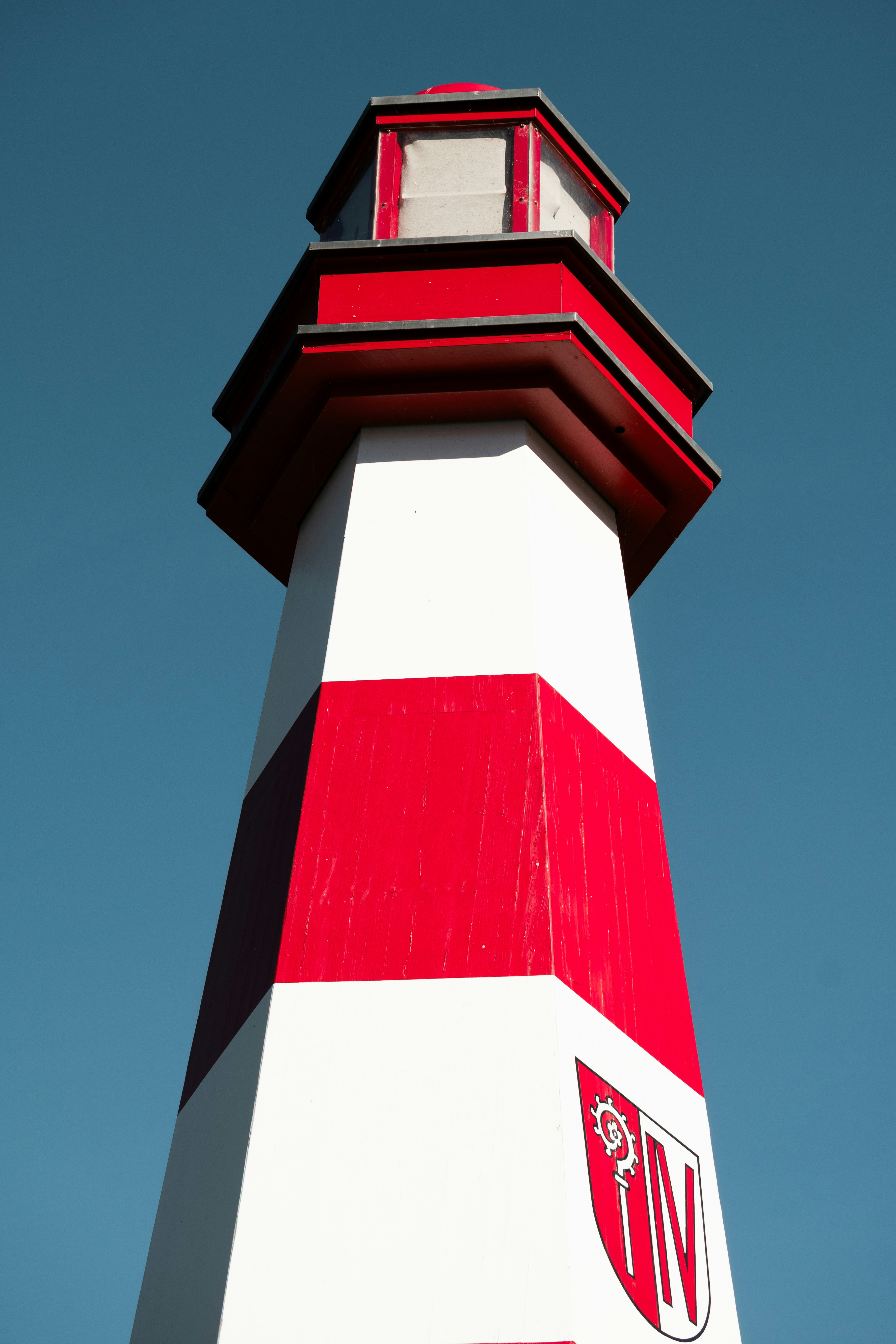 Red-and-white lighthouse rising against a deep blue sky