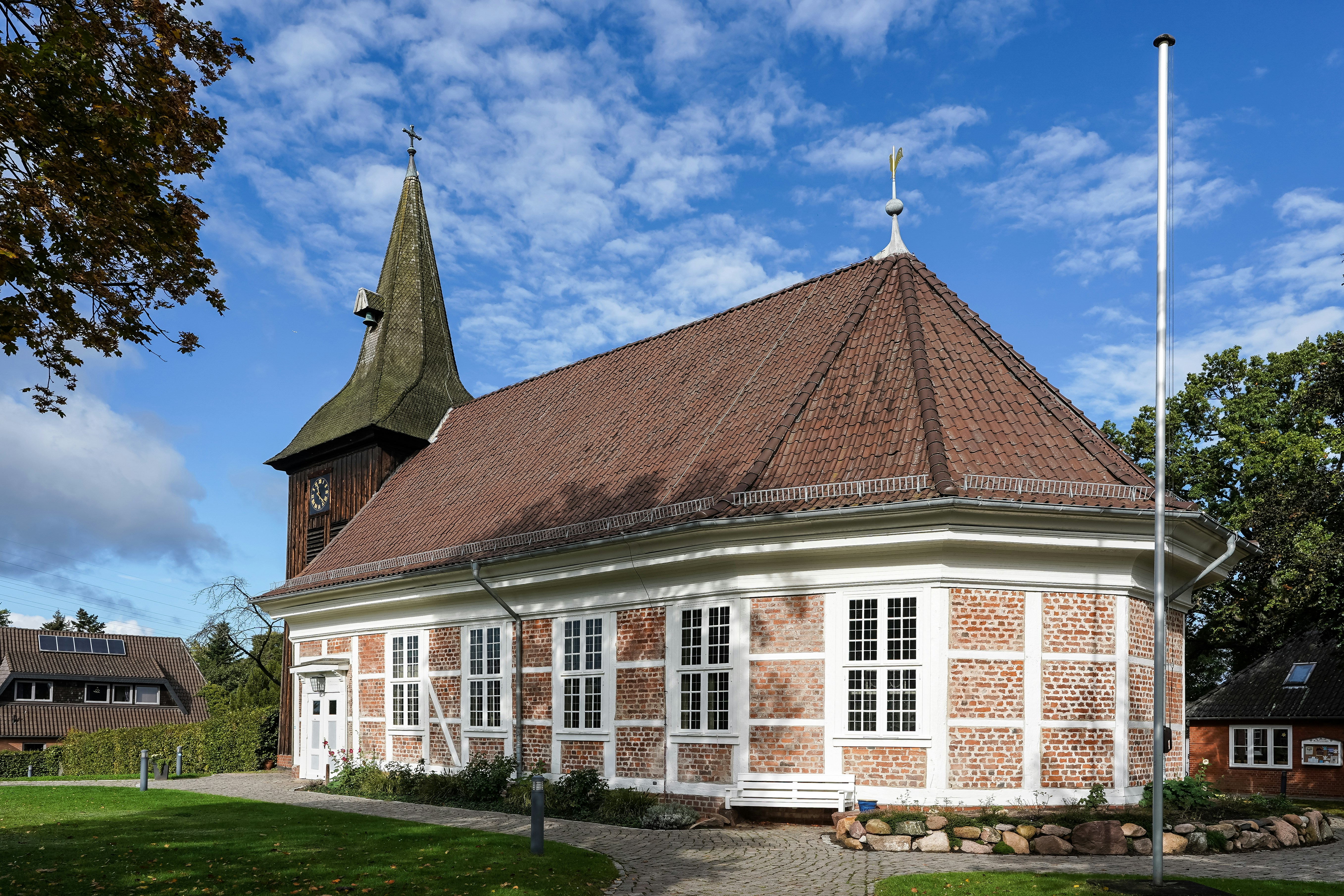 Historic brick hall under a steep gabled roof near a verdant lawn