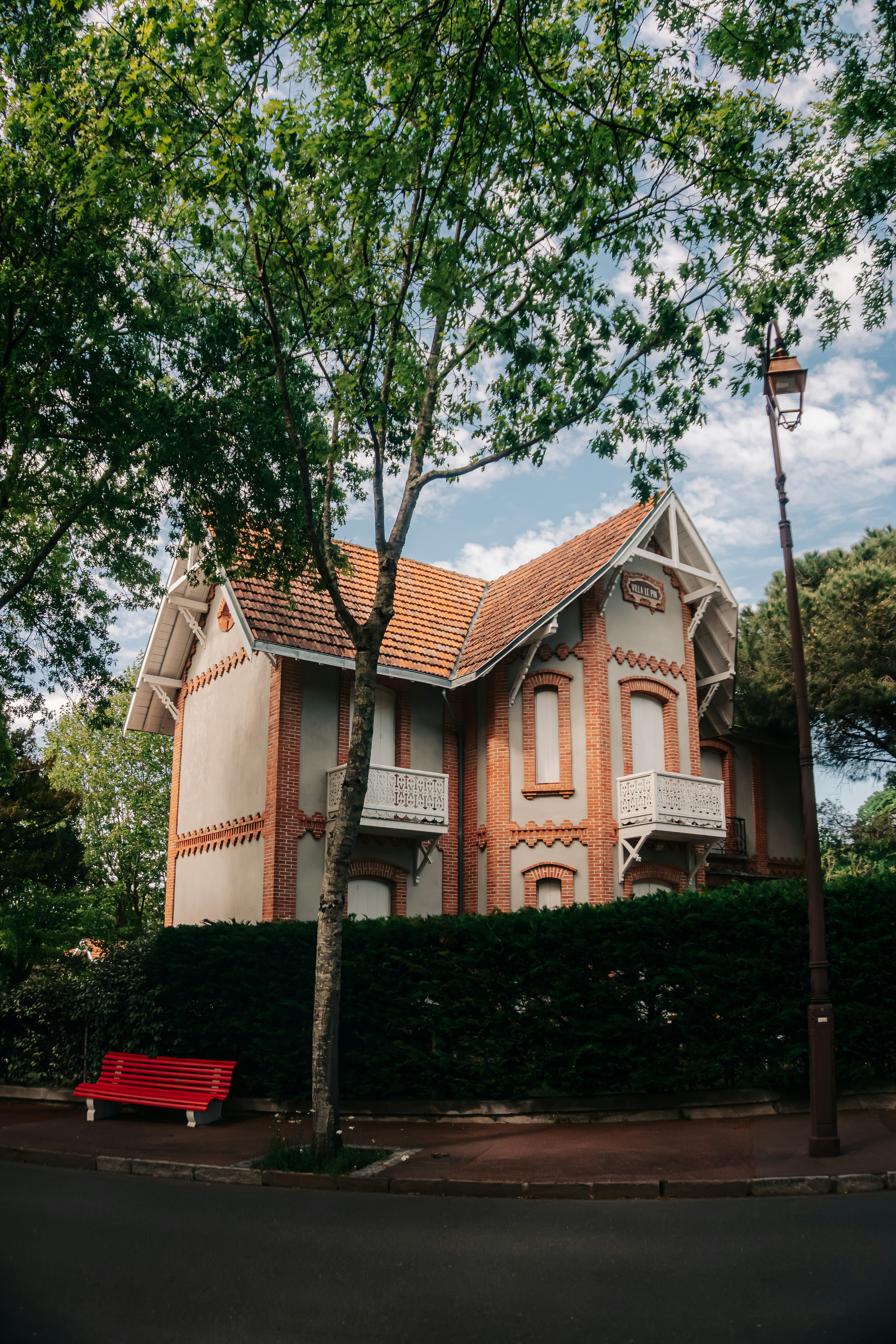Brick-and-White Villa Beside a Quiet Street Surrounded by Trees