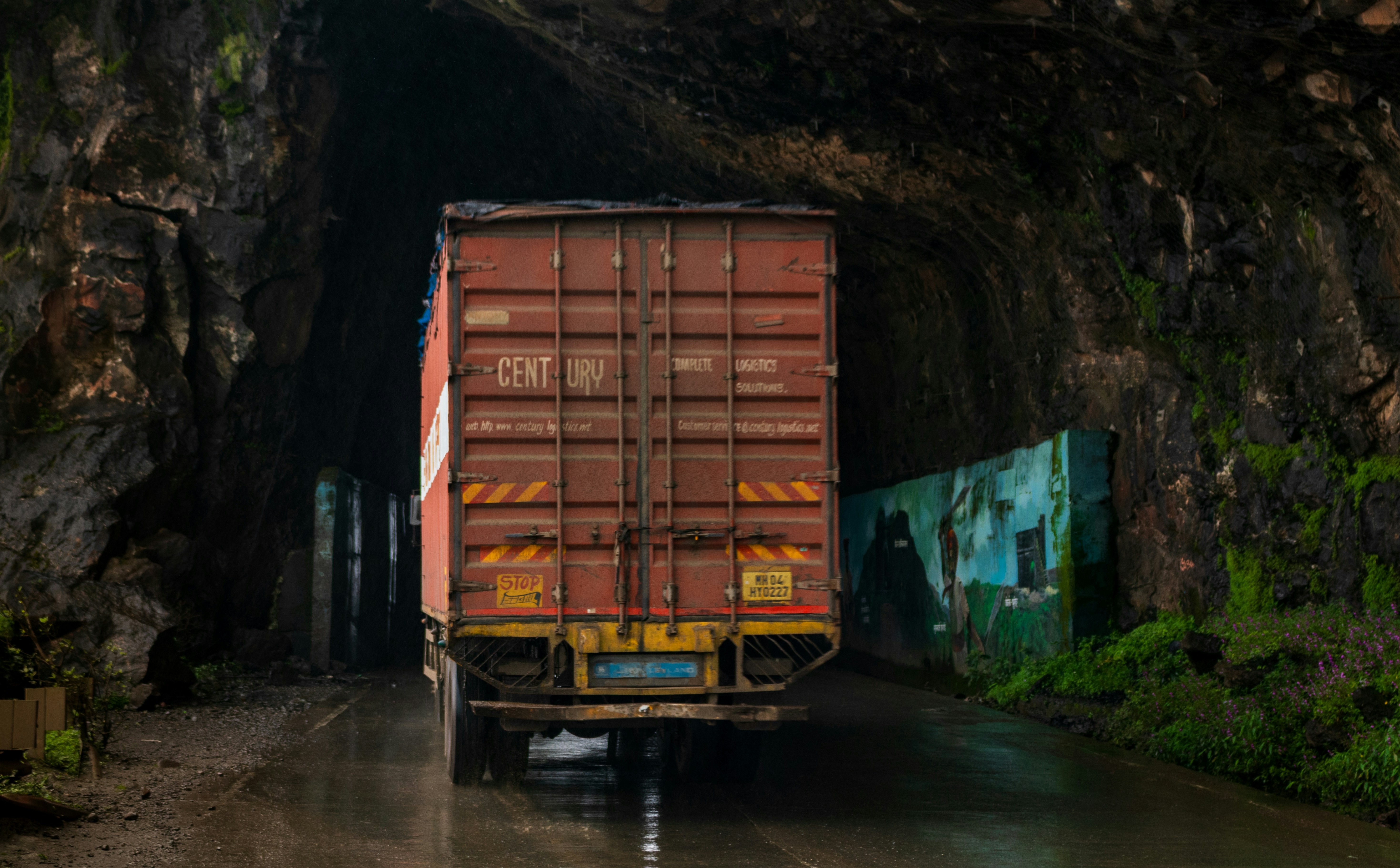 Truck into a dim cave of rock and rain-soaked road