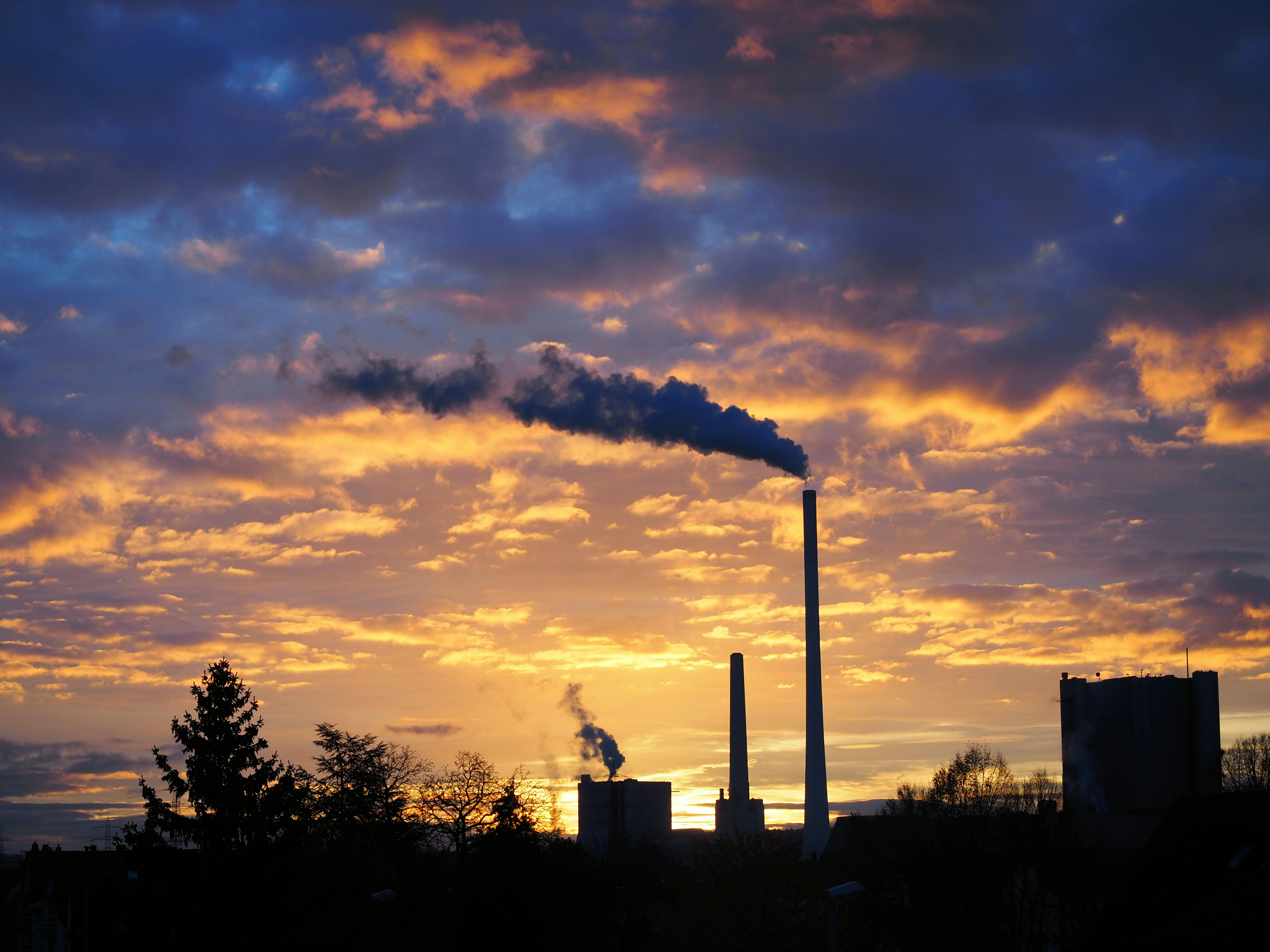 Sunset Over Industry: Silhouettes Behind a Smoke-tinged Horizon