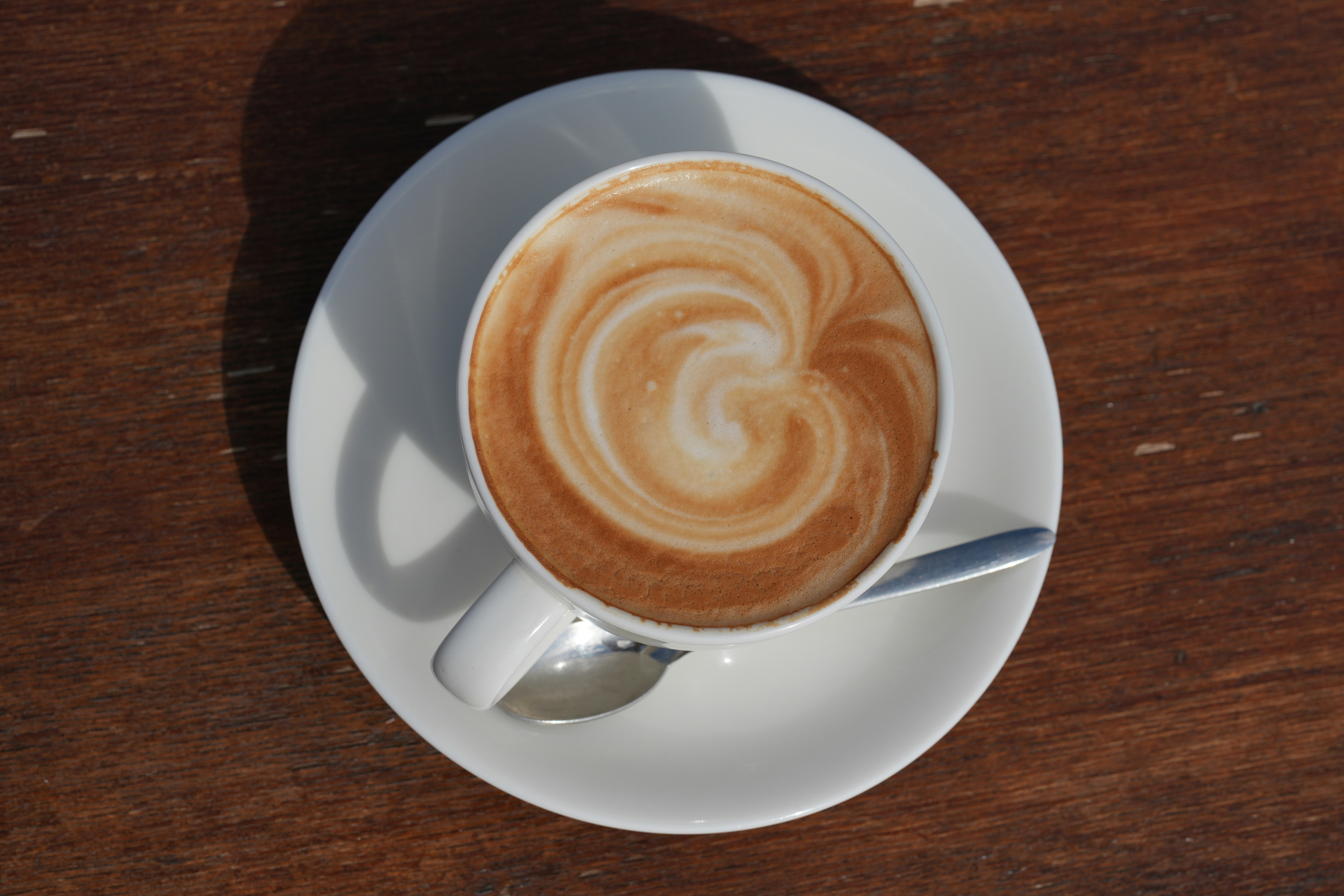 A Cup of Swirled Warmth on a Dark Wood Table