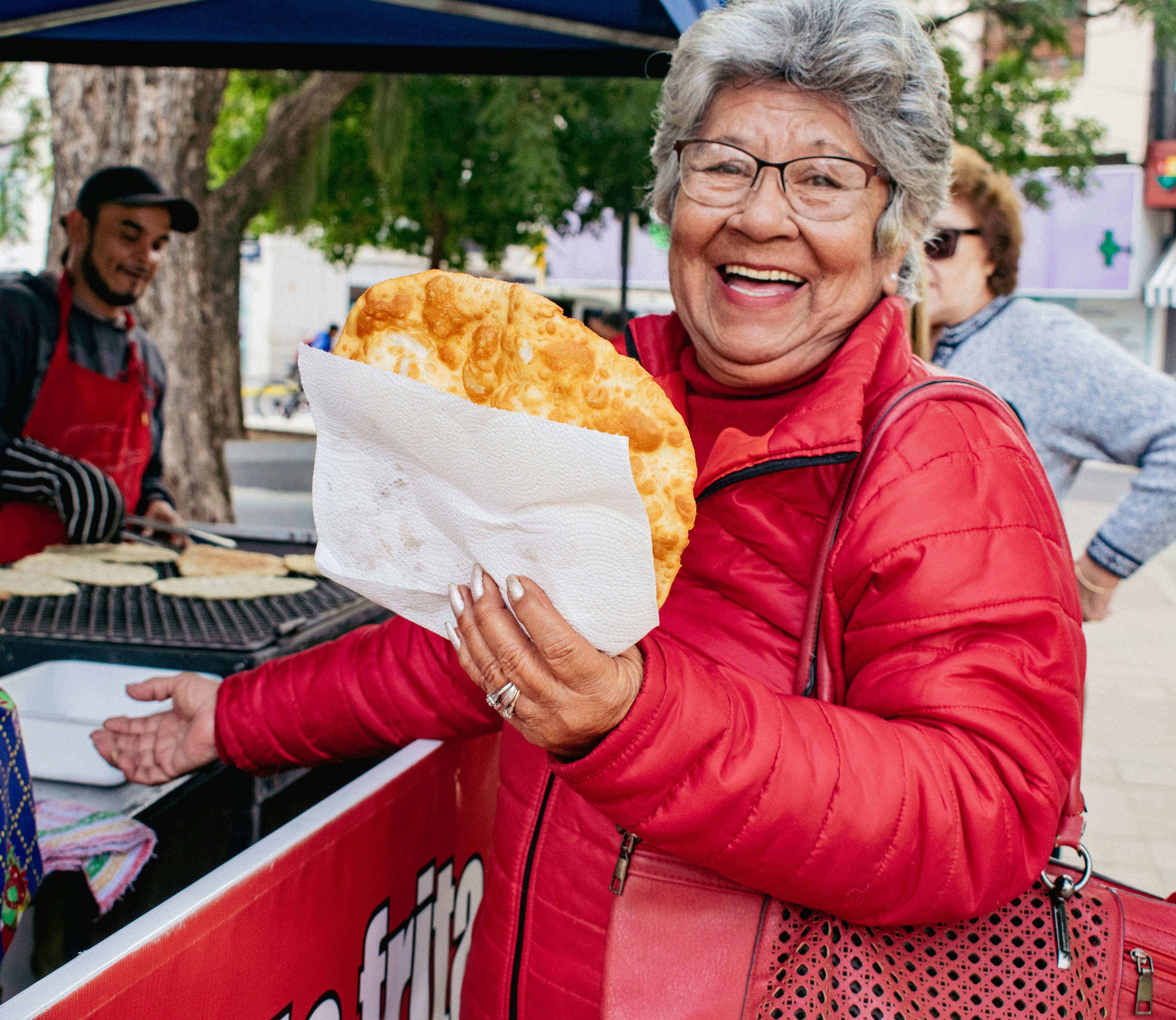 Smiling Vendor with Folded Crepe Under a Tent