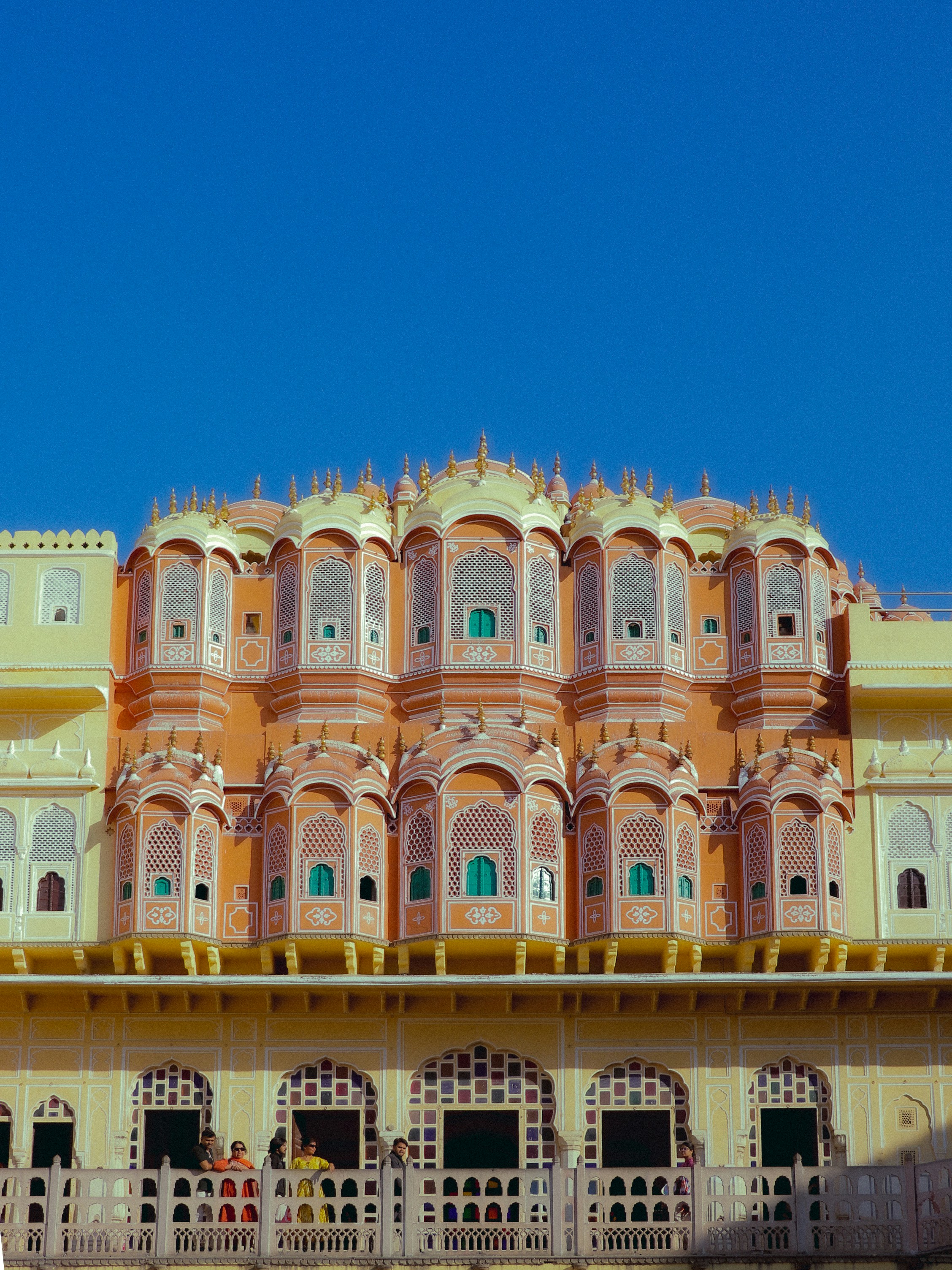 Sunlit Facade of Havelis: Carved Pavilions Rise Under a Clear Indigo Sky