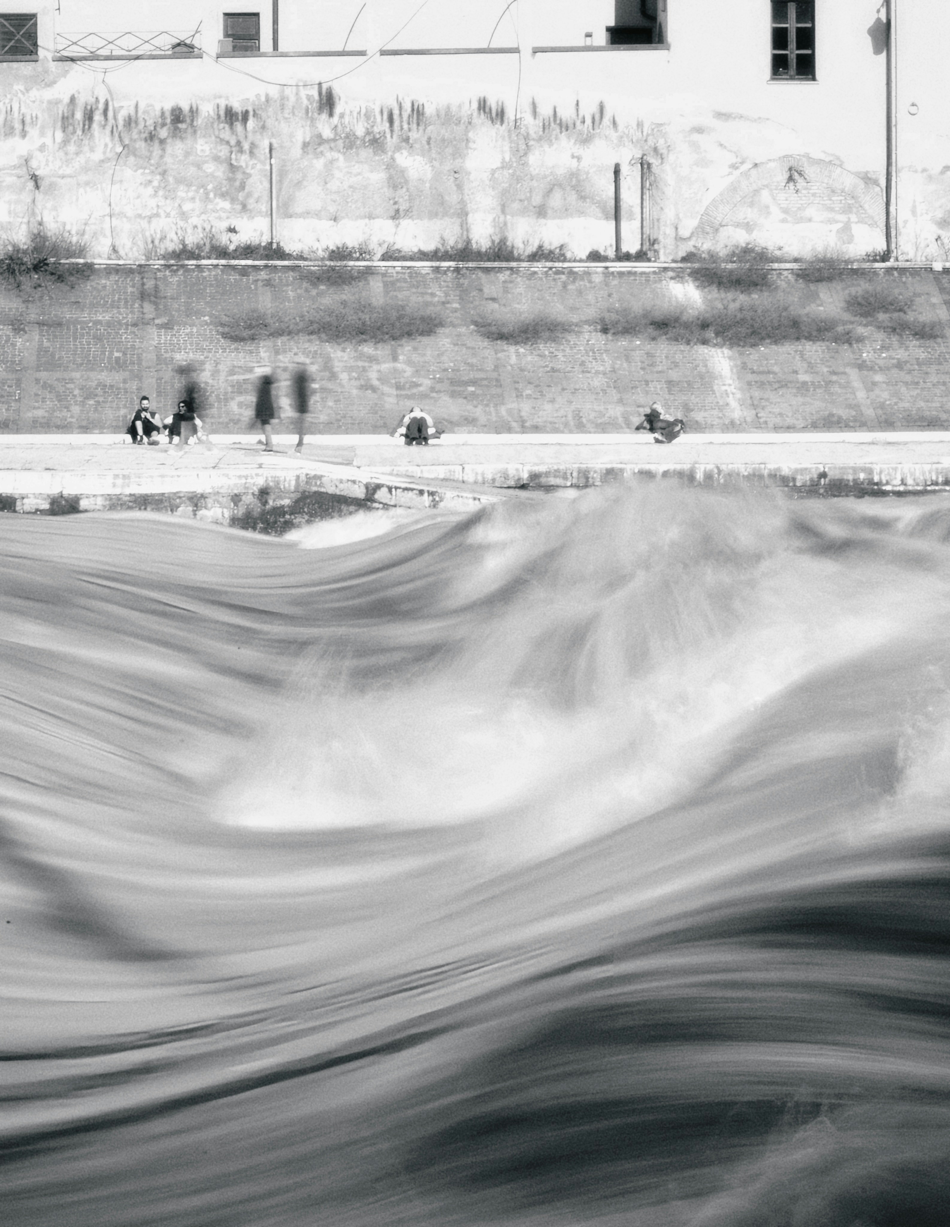 Motion in Distant Quiet: People by the Riverbank Framed by Surging Waves