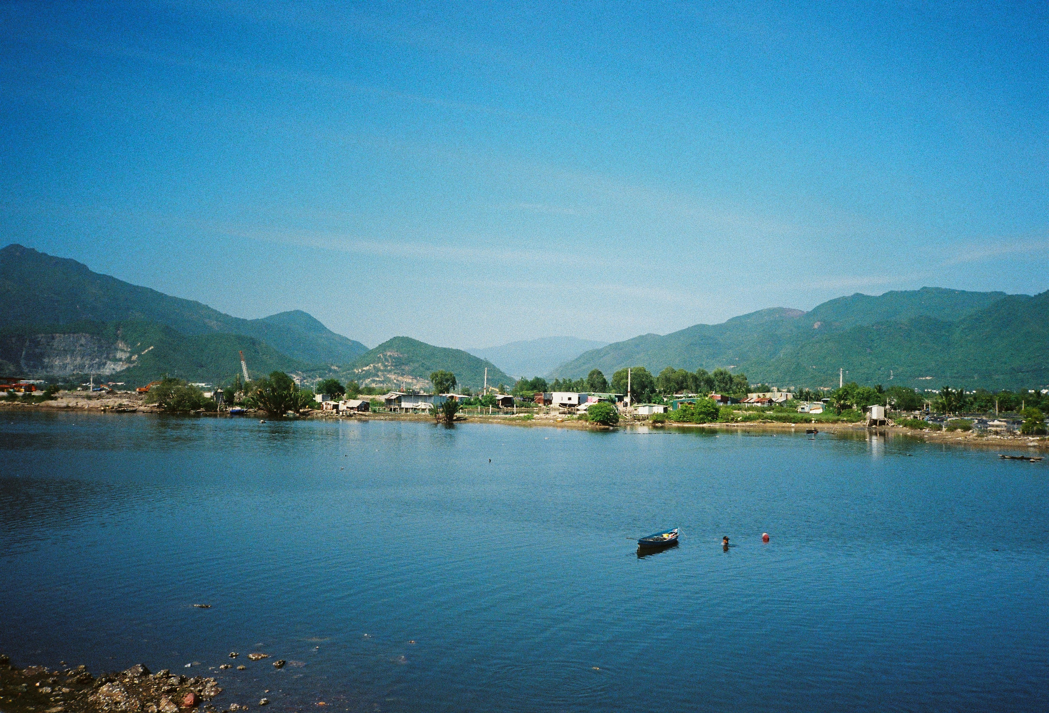 Quiet lakeside village under a blue arc of hills