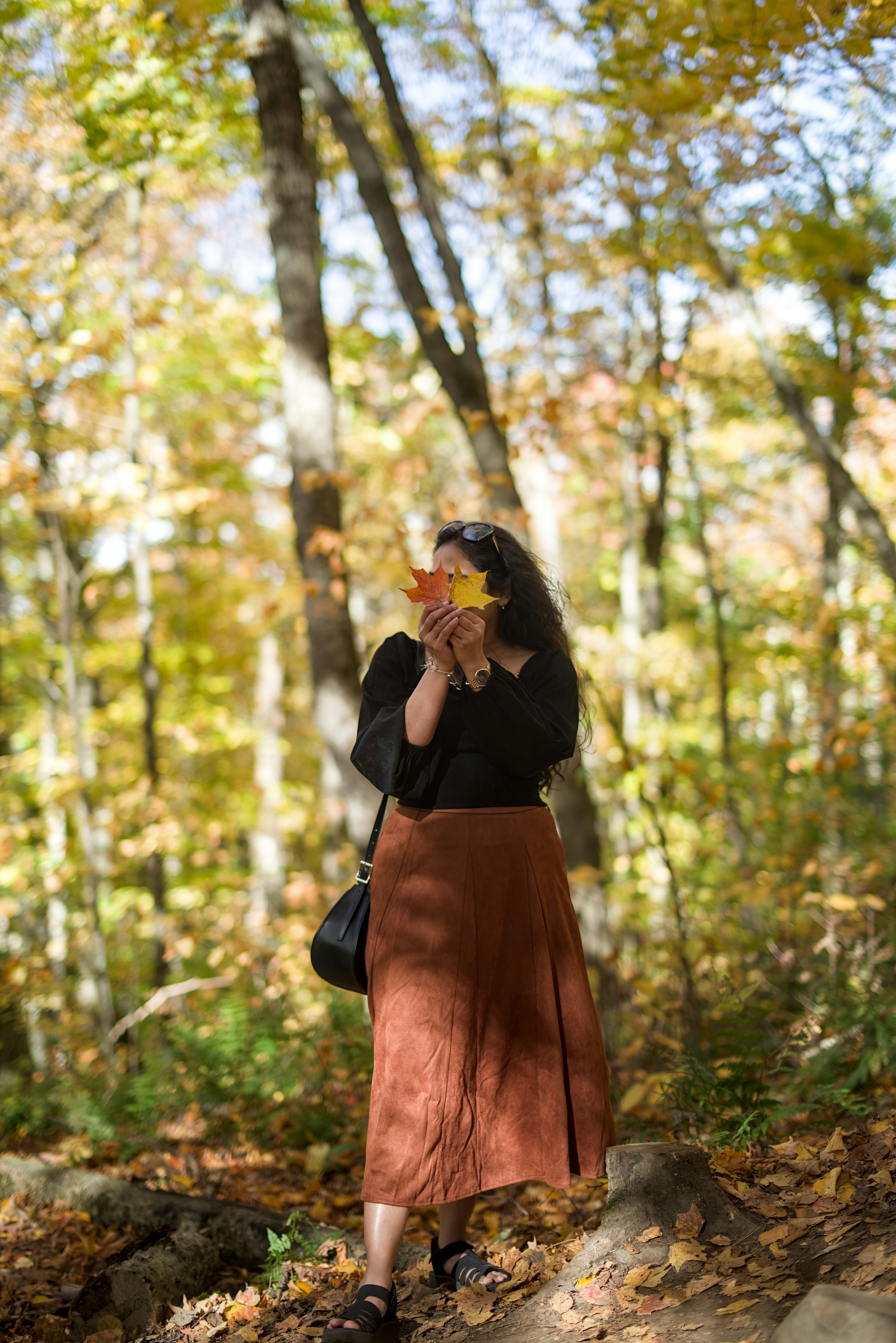 Autumn's Quiet Portrait: A Woman with Leaves in a Sunlit Forest