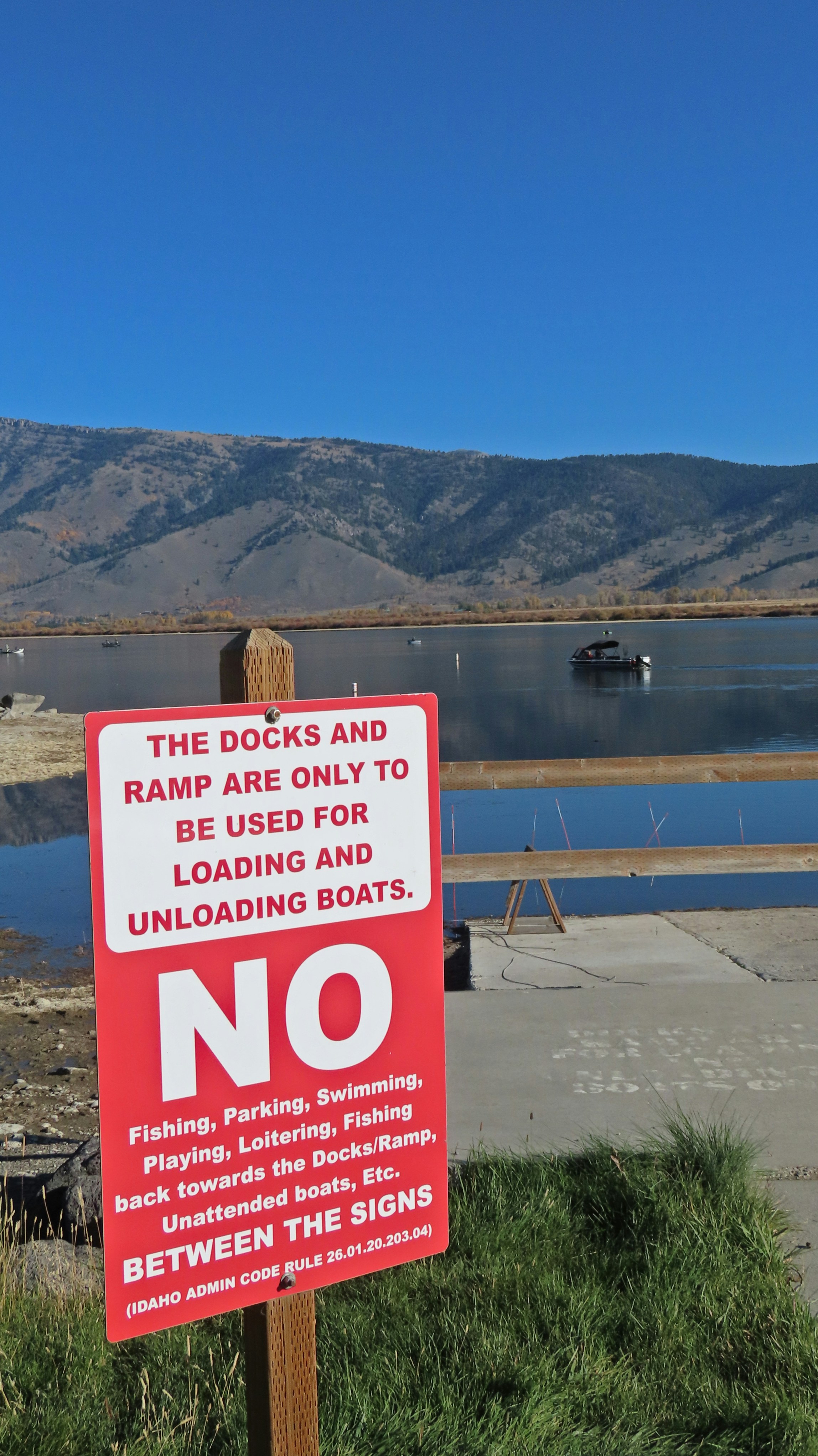 Red Sign at the Edge: A Quiet Lakefront Under Wide Blue
